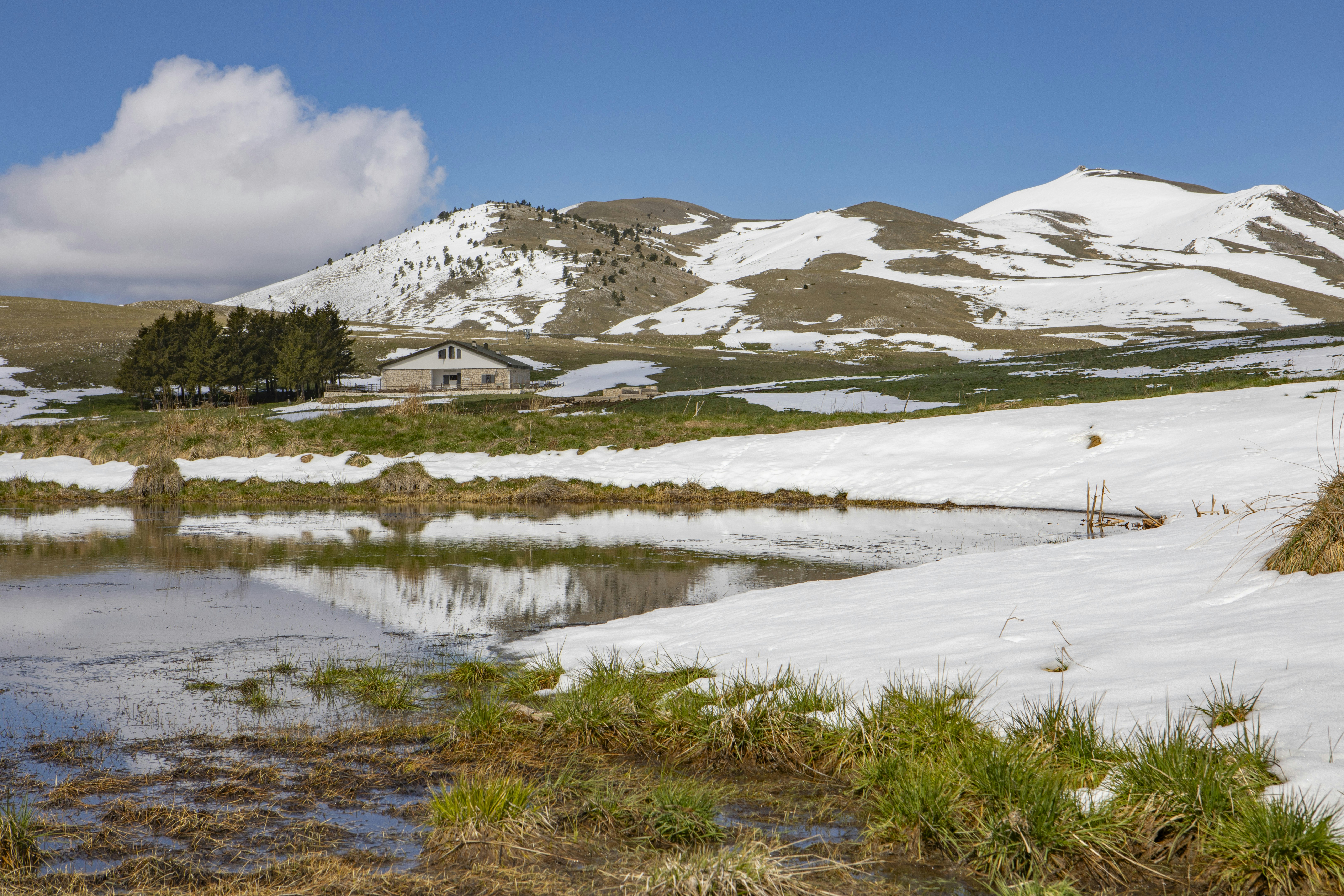 Lone Cabin in a Snow-Kissed Alpine Valley Beneath a Clear Blue Sky