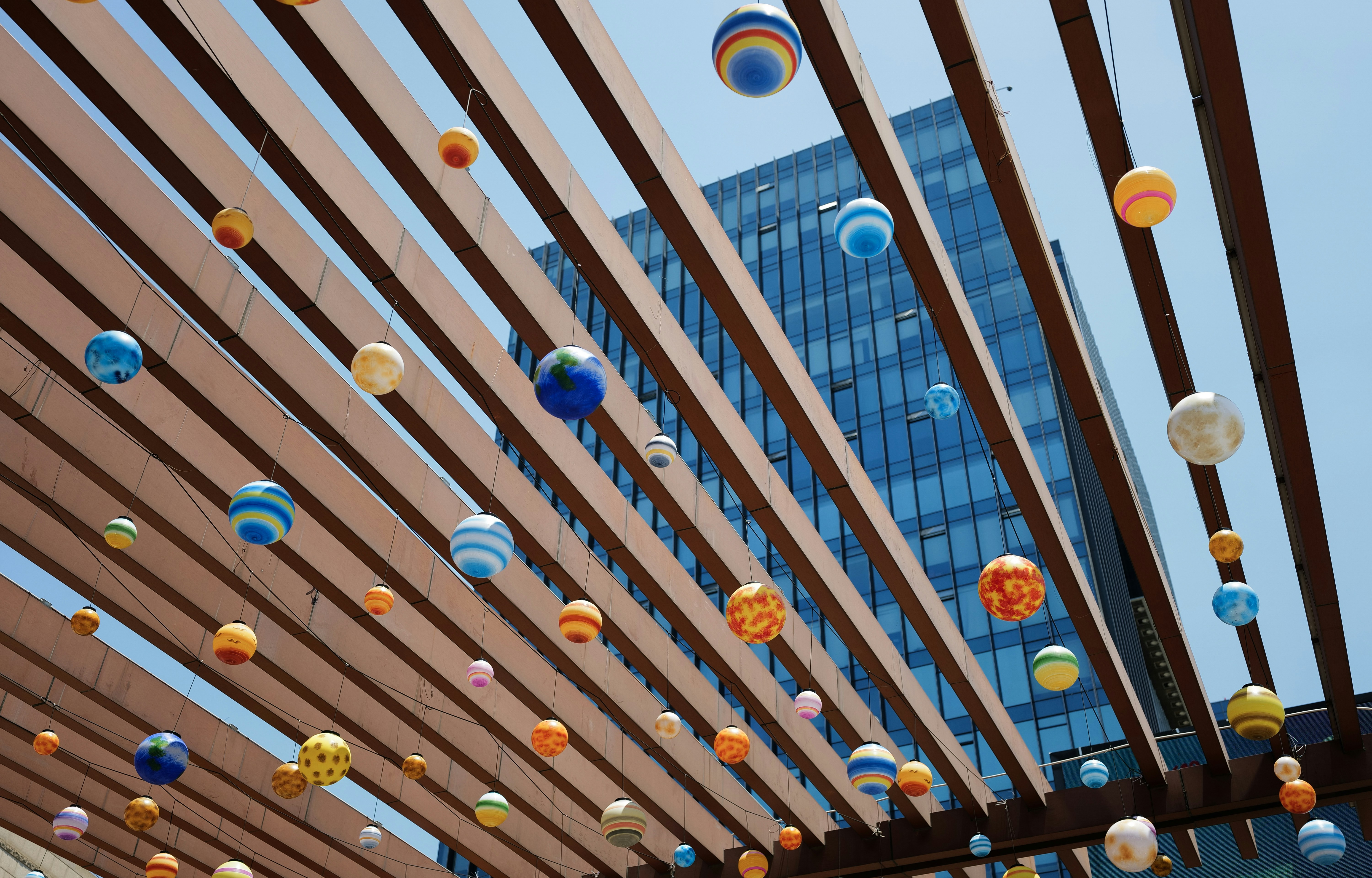 Orbs in Flight: Colorful Glass Spheres Draped Across a Wooden Lattice Canopy