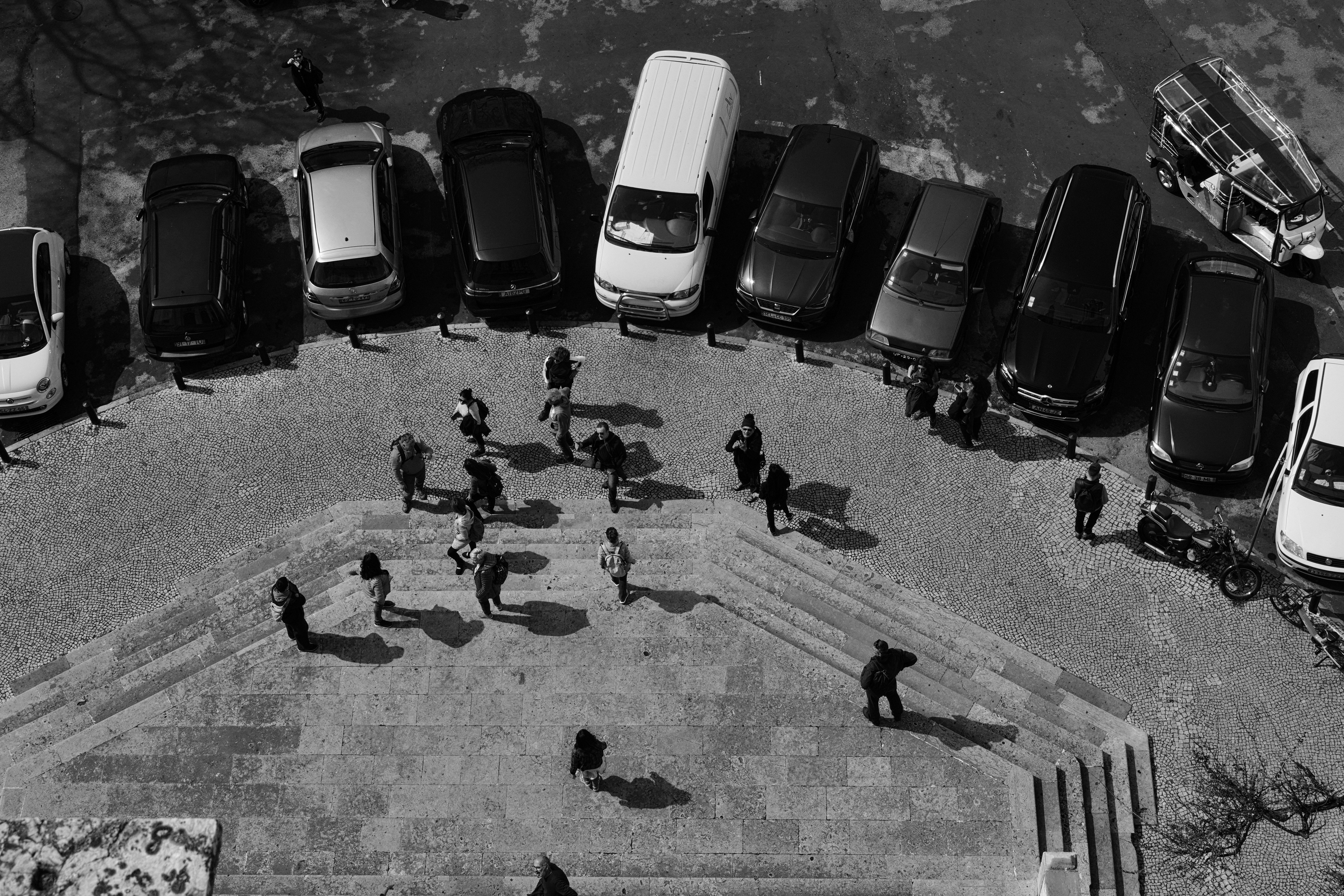 A group of people walking down a street next to parked cars photo ...