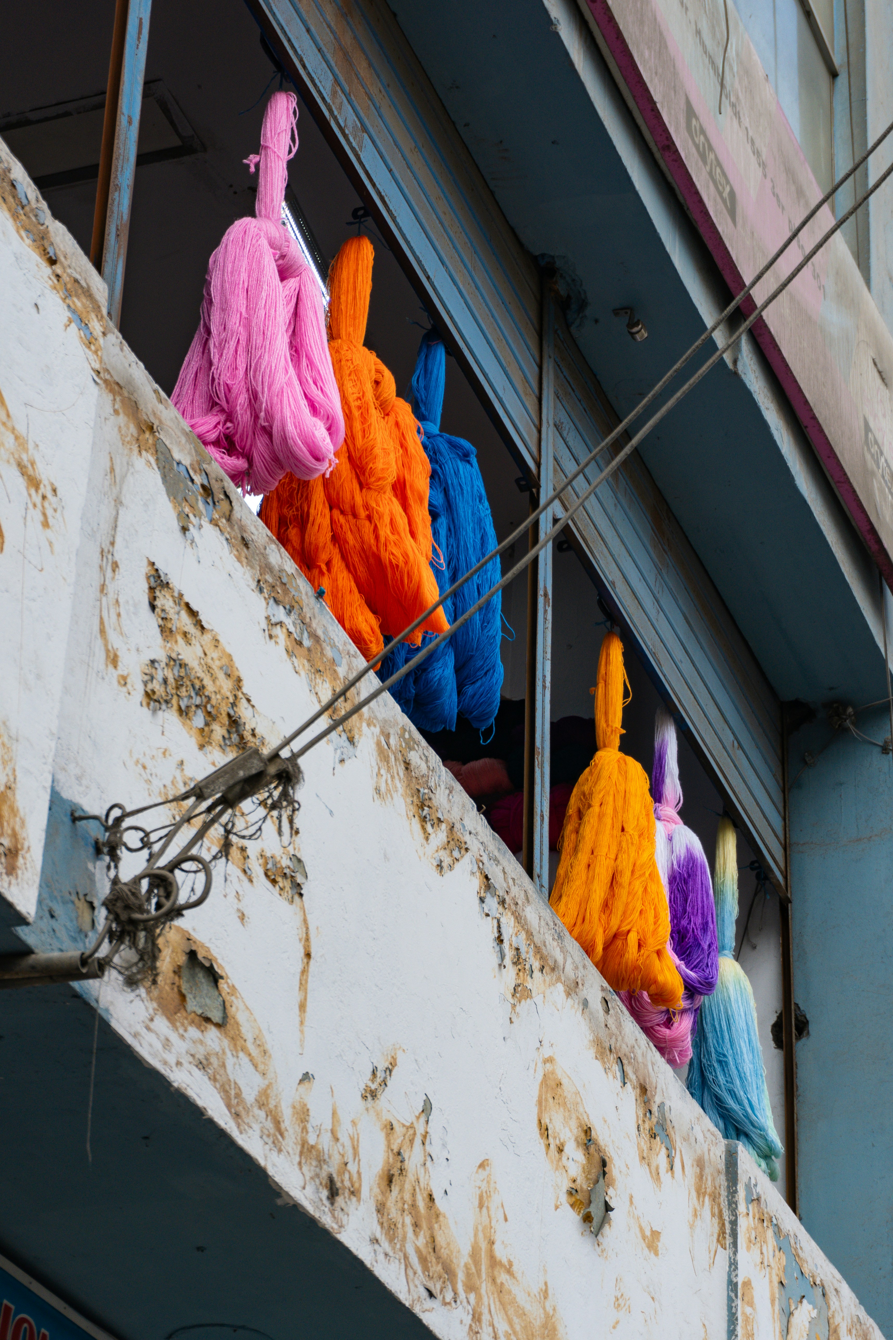 A bunch of colorful yarn hanging from a building photo – Free Gamarra ...