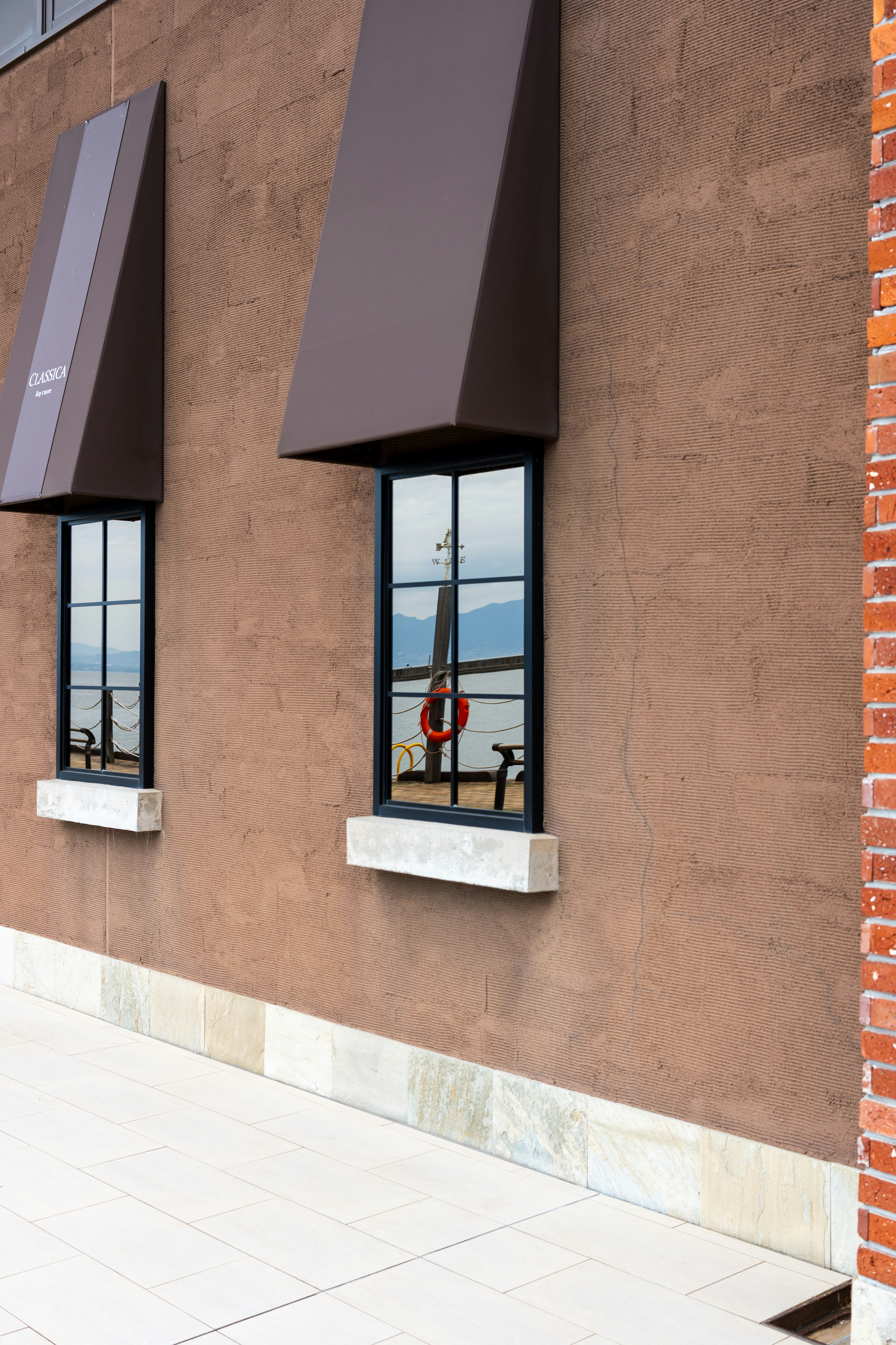 Orange Lifebuoy Framed by Harbor Window in a Brick-Brown Facade
