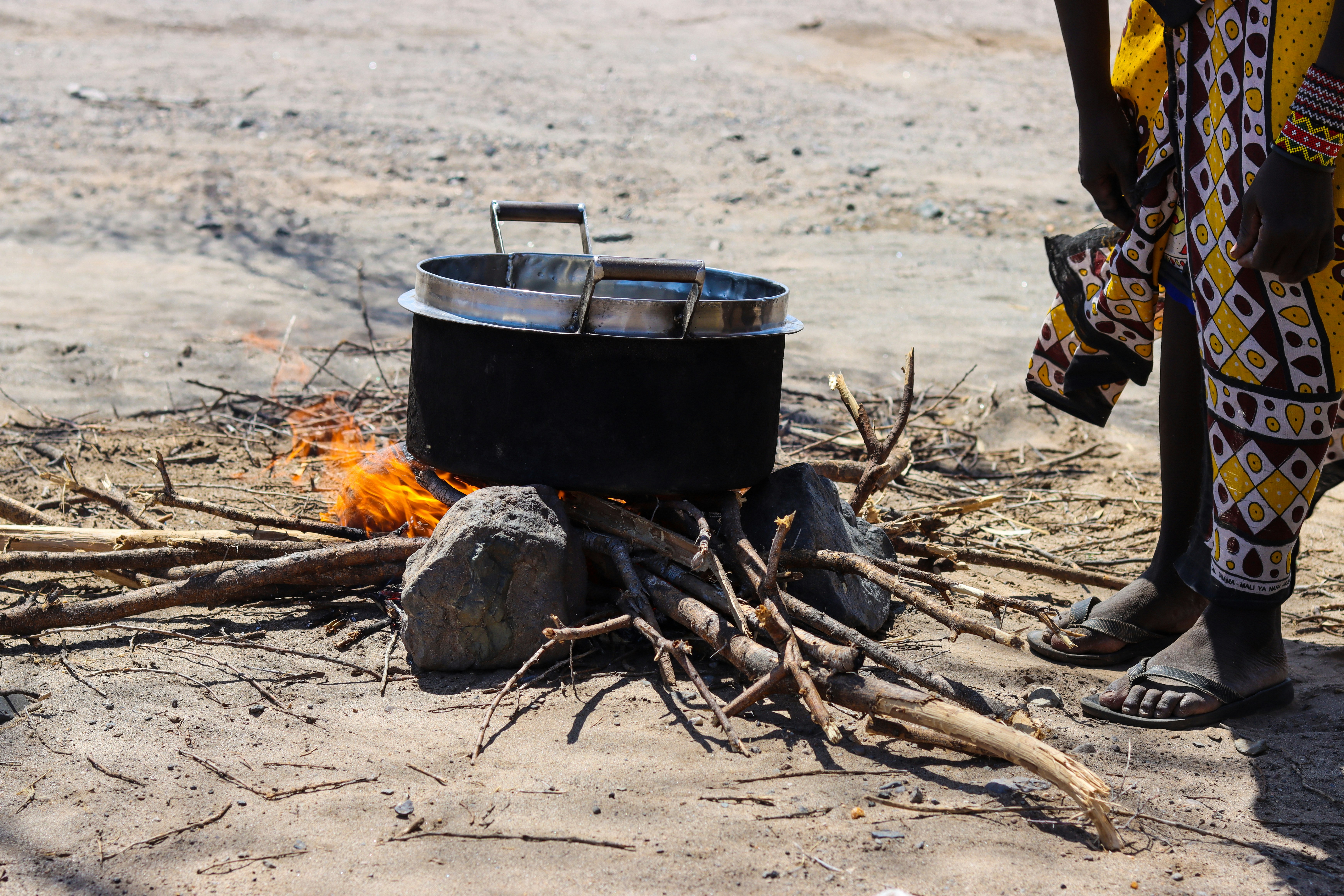 Ember Ring: A Pot Simmering over a Sunlit Campfire on a Dusty Plain