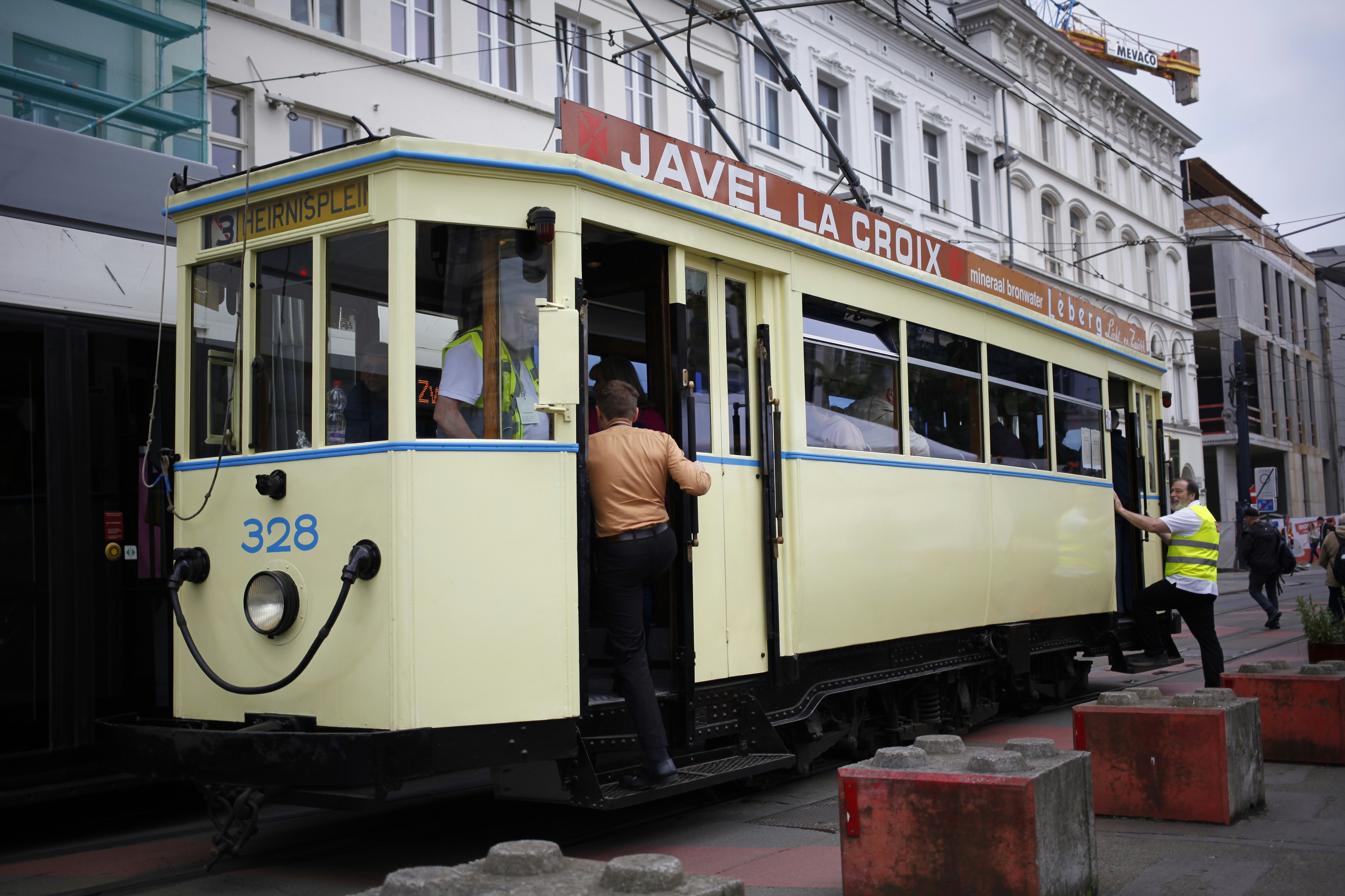 Open-Door Transit: Cream Tram at the Edge of a Busy City Street