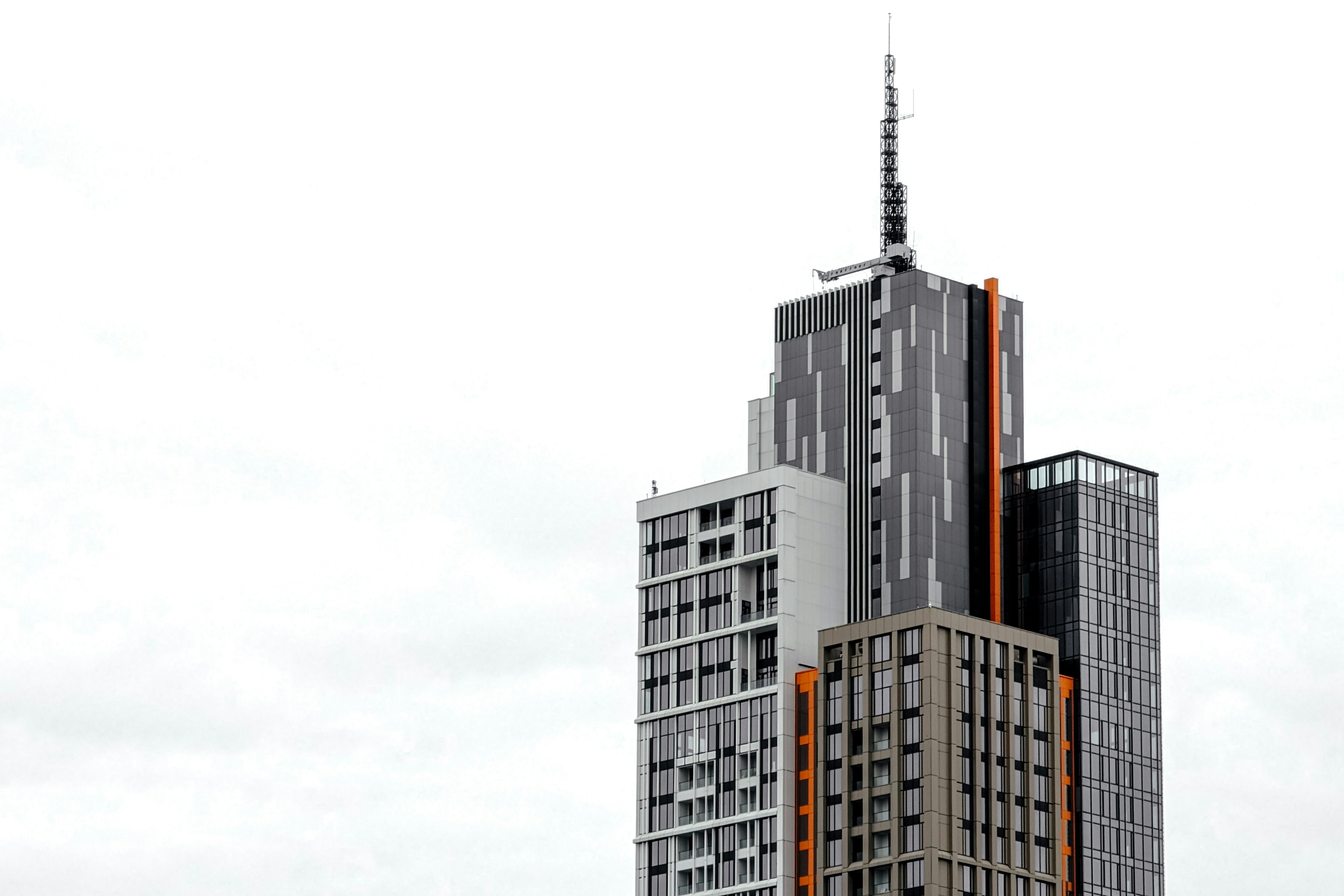 Tall modern building with a clock at the peak against a cloudy sky.
