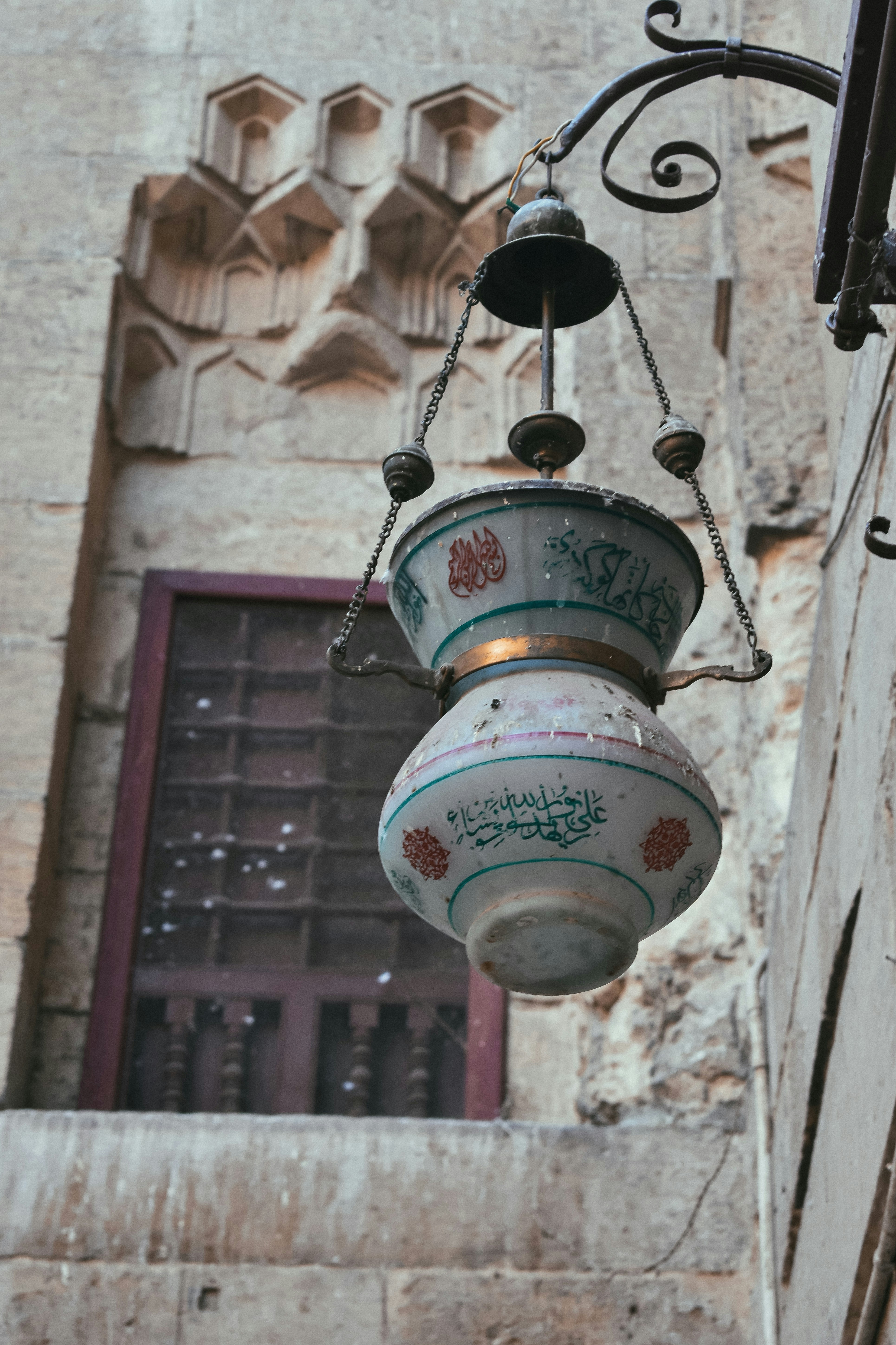 Whispered Light: A suspended porcelain lantern before a carved stone wall