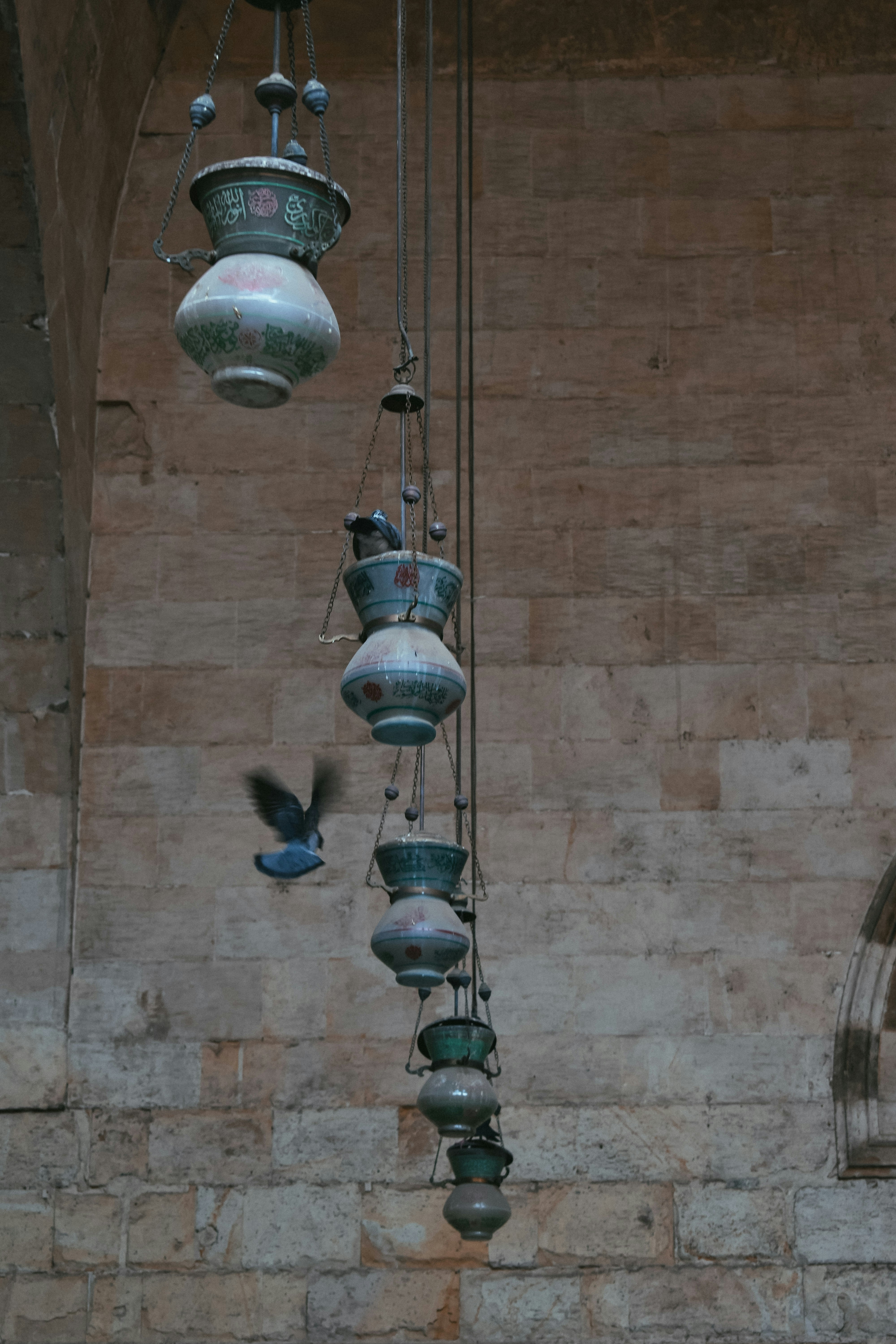 Suspended Ceramics: A Vertical Line of Ornate Vessels in a Stone Corridor