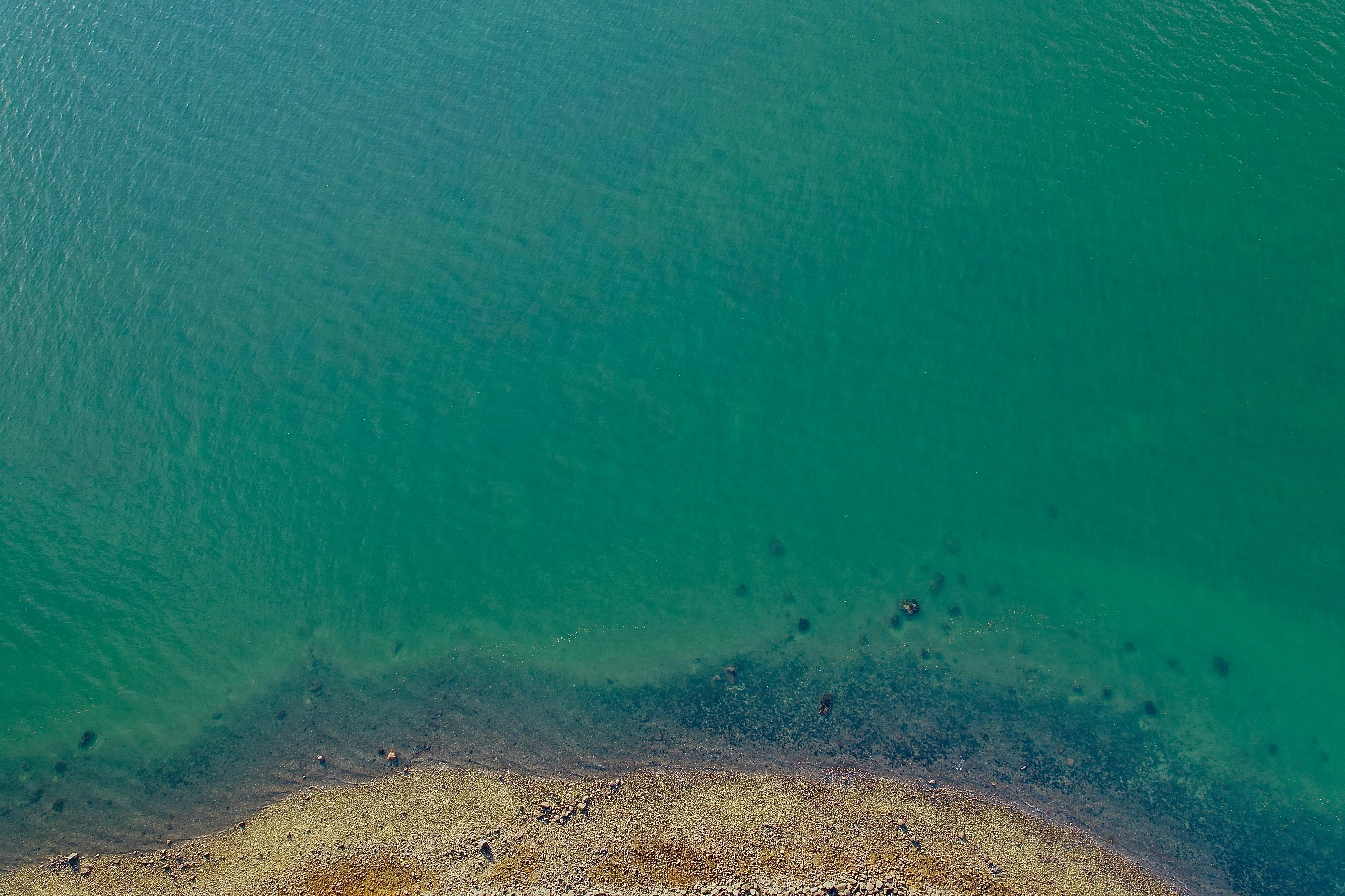 Aerial view of a tranquil turquoise shoreline meeting sandy beach.