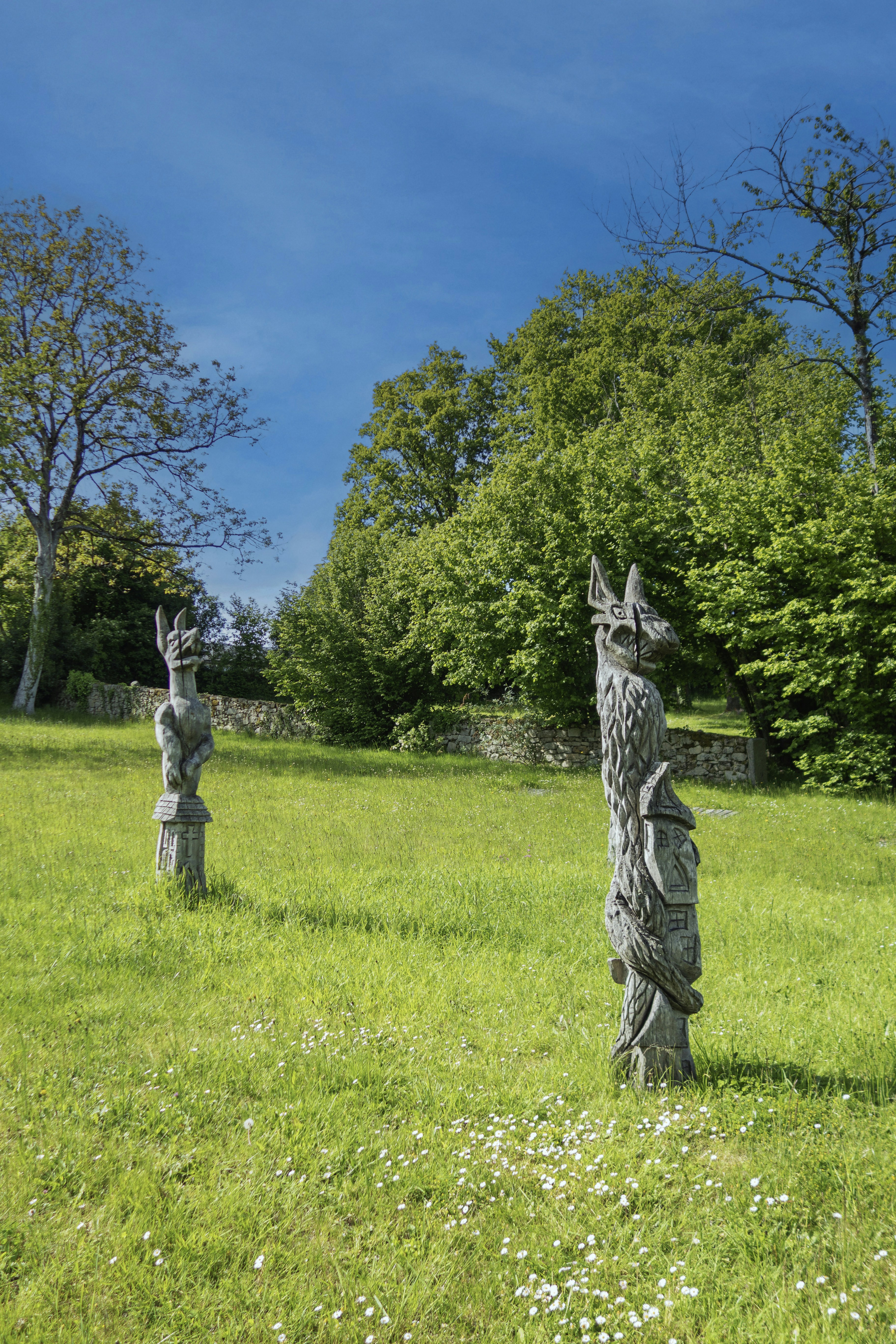 A couple of statues sitting on top of a lush green field photo – Free ...