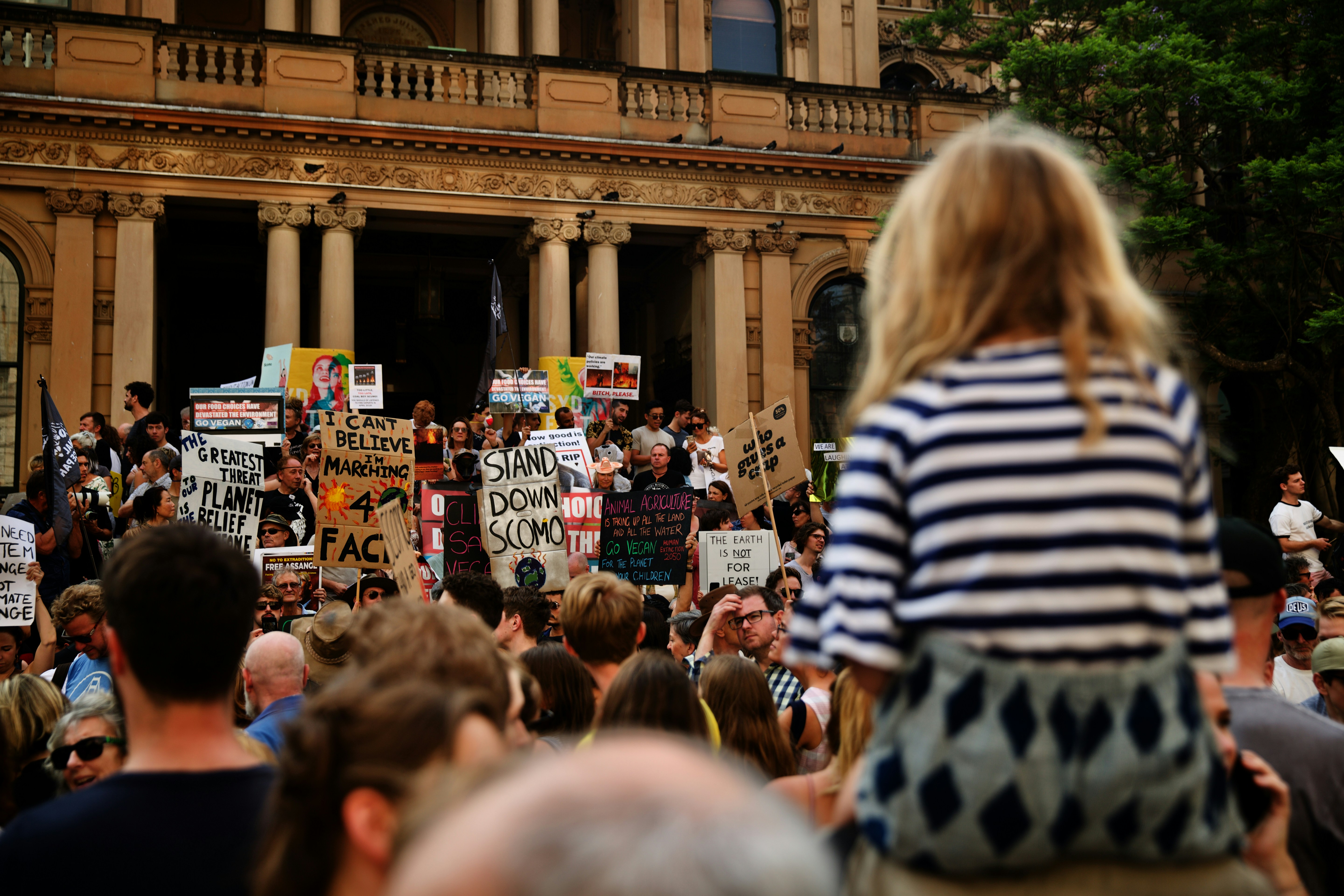 A crowd of people holding up signs in front of a building photo – Free ...