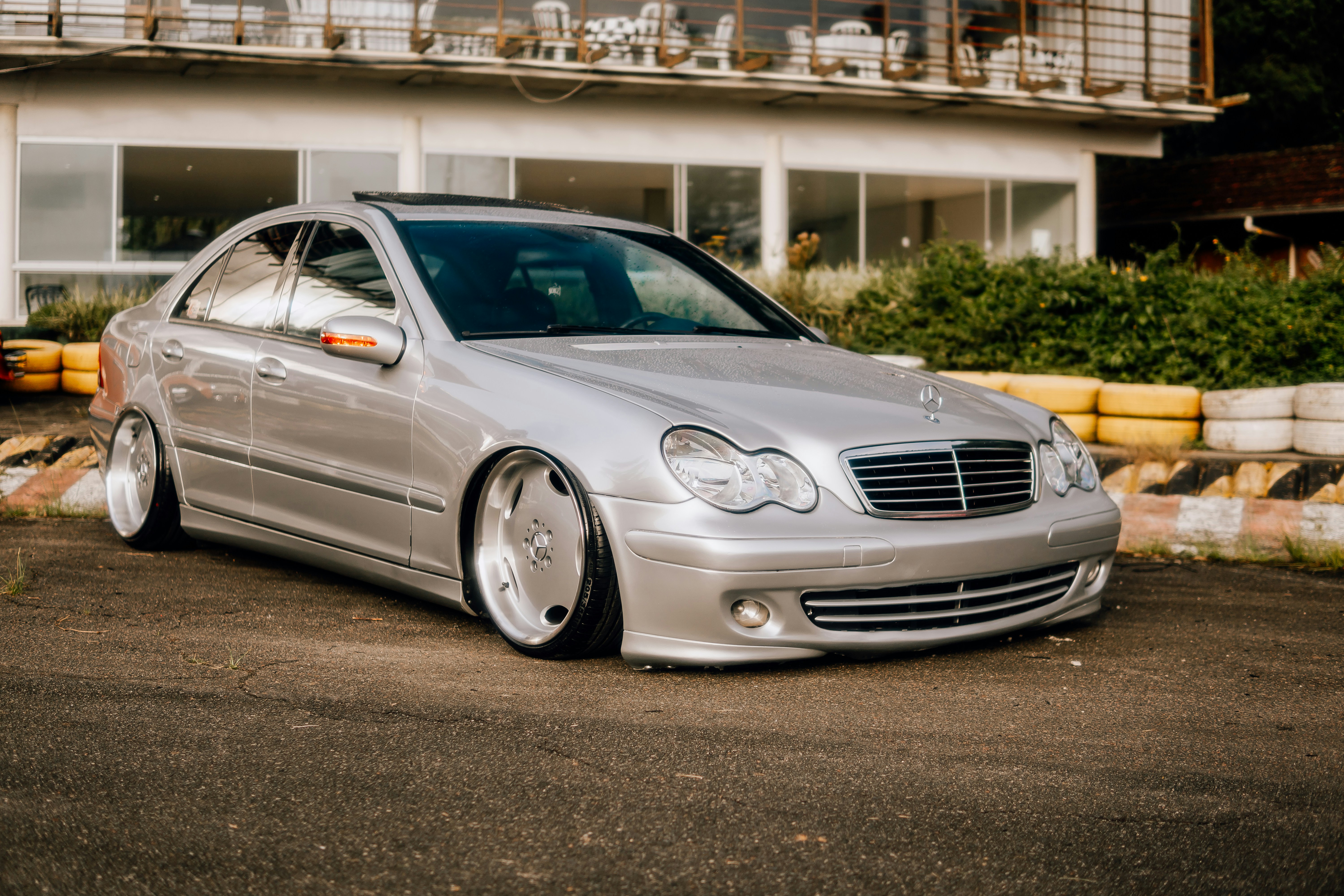 Silver sedan with lowered stance resting near a raceway backdrop