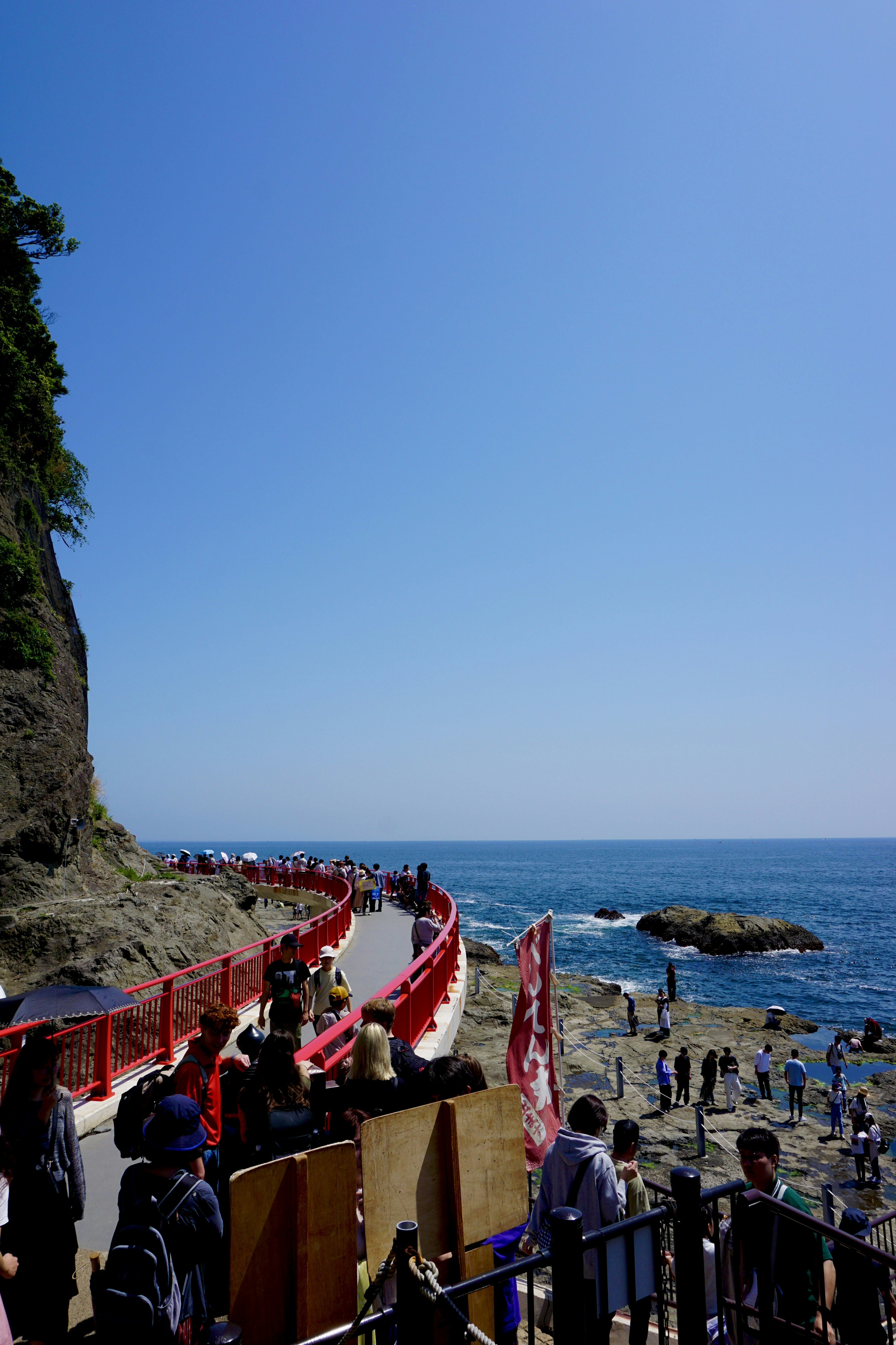 Red Rail Over the Sea: Crowded Cliffside Promenade toward the Horizon