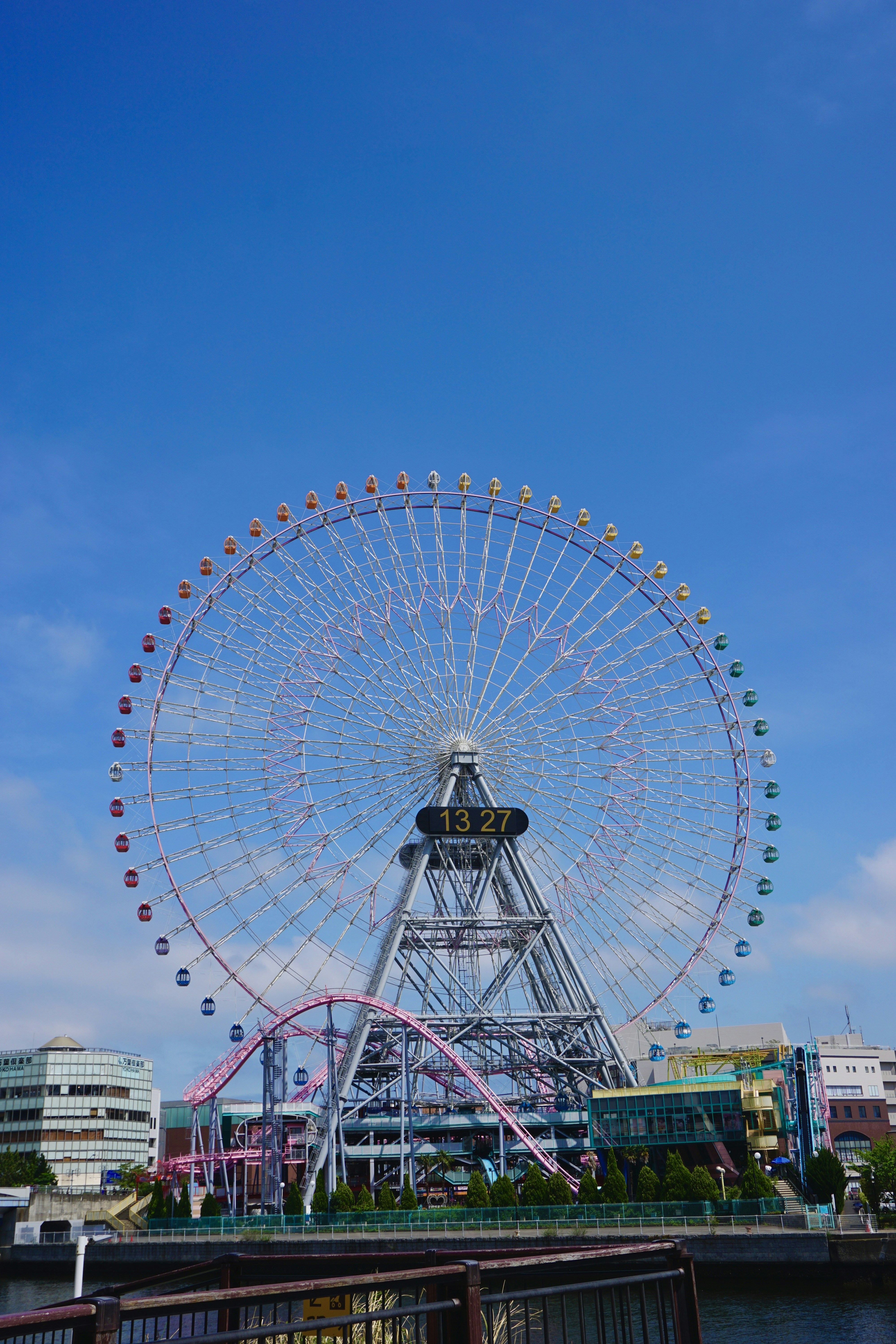 Clockwork in the Blue: Ferris Wheel Crowned by Riverside Rides