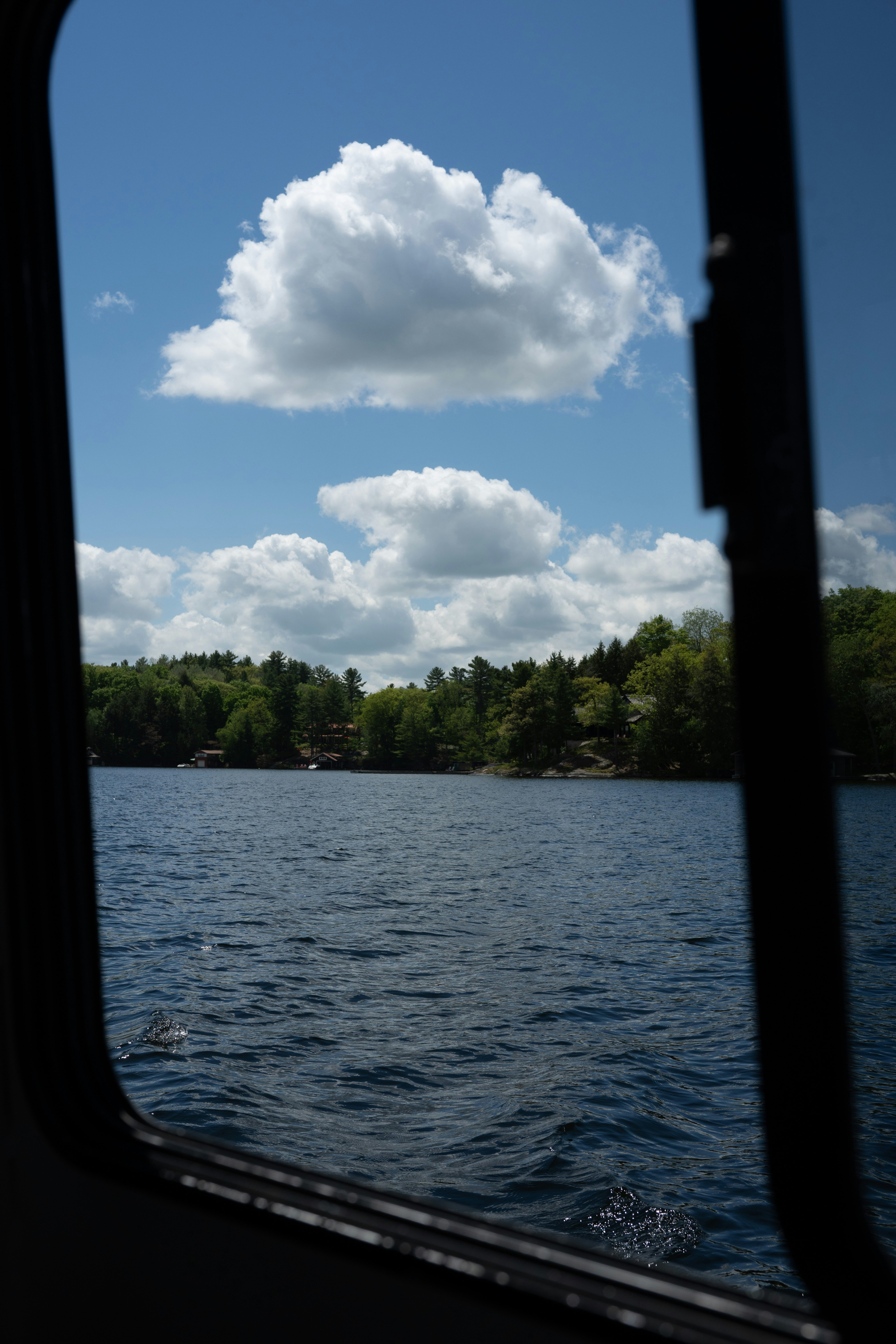 Azure Lake Vista: Clouds Framed by a Boat Window