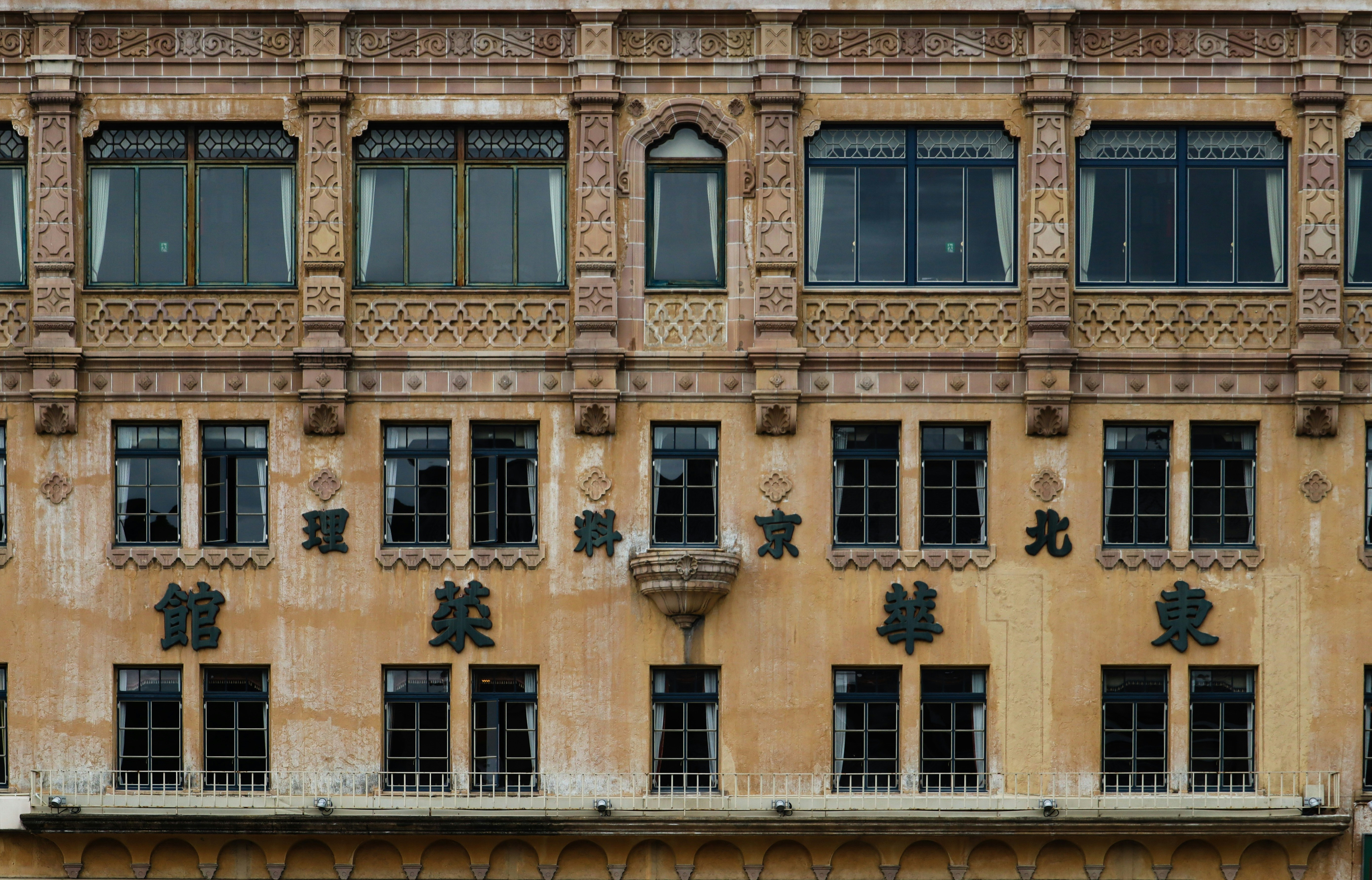 Central Balcony Amidst a Weathered Facade Inscribed with Chinese Characters