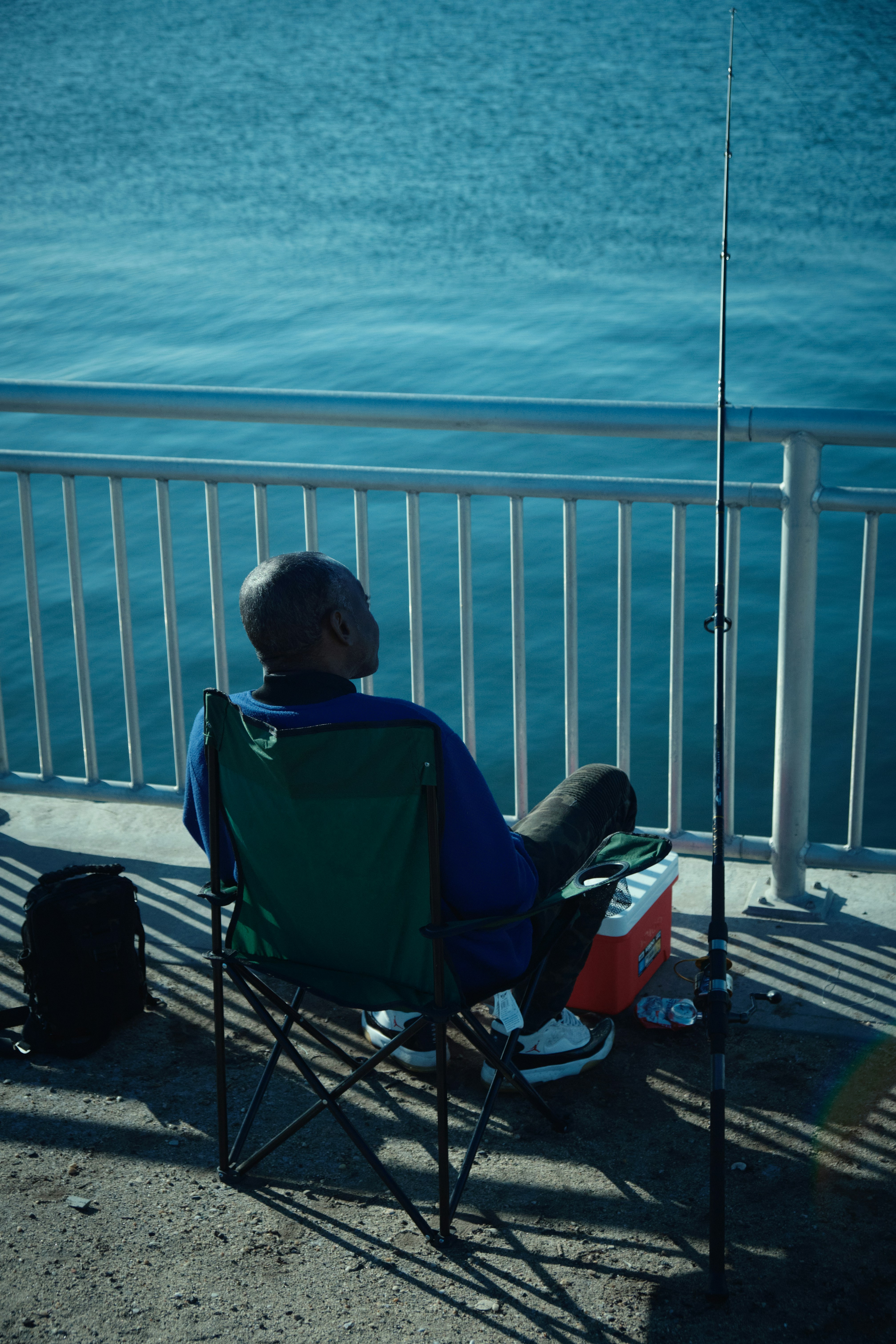 Blue Railings, Quiet Rod: A Pier-Side Moment of Stillness