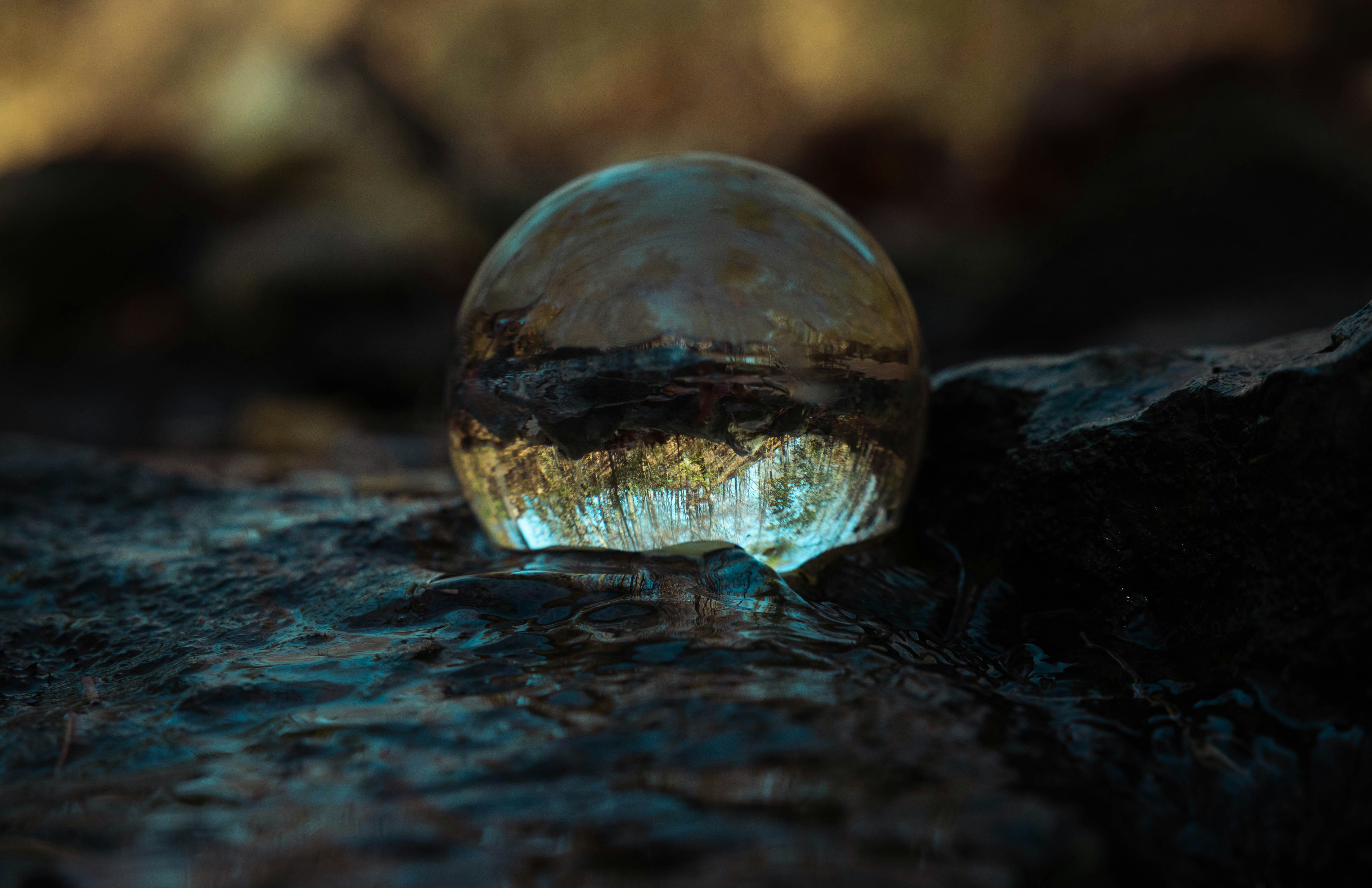 Moonlit Marble: A Glass Orb Reflecting a Hidden Landscape on Wet Stone