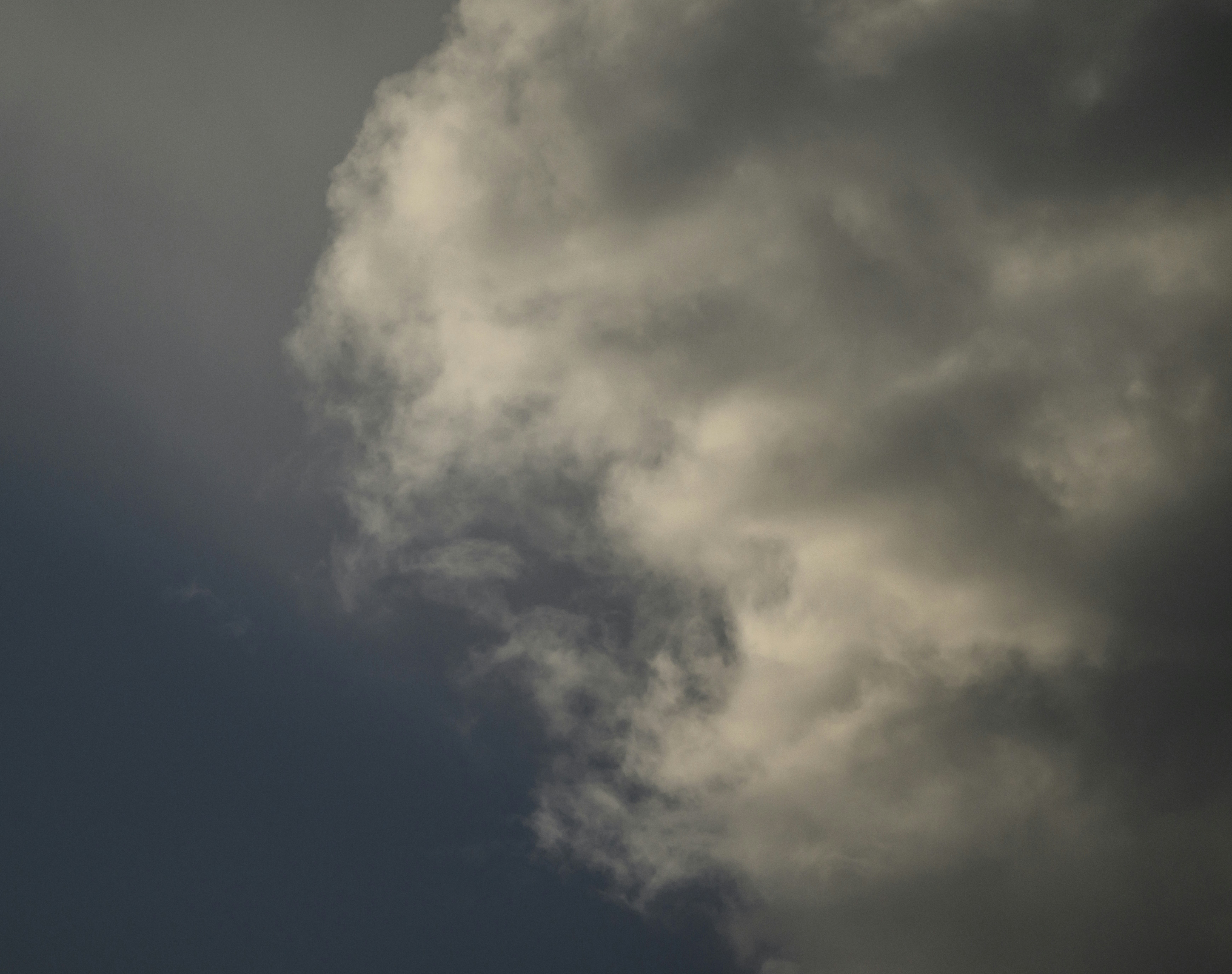 Dramatic cloud formations juxtaposed against a deep blue sky, highlighting the interplay of light and shadow.