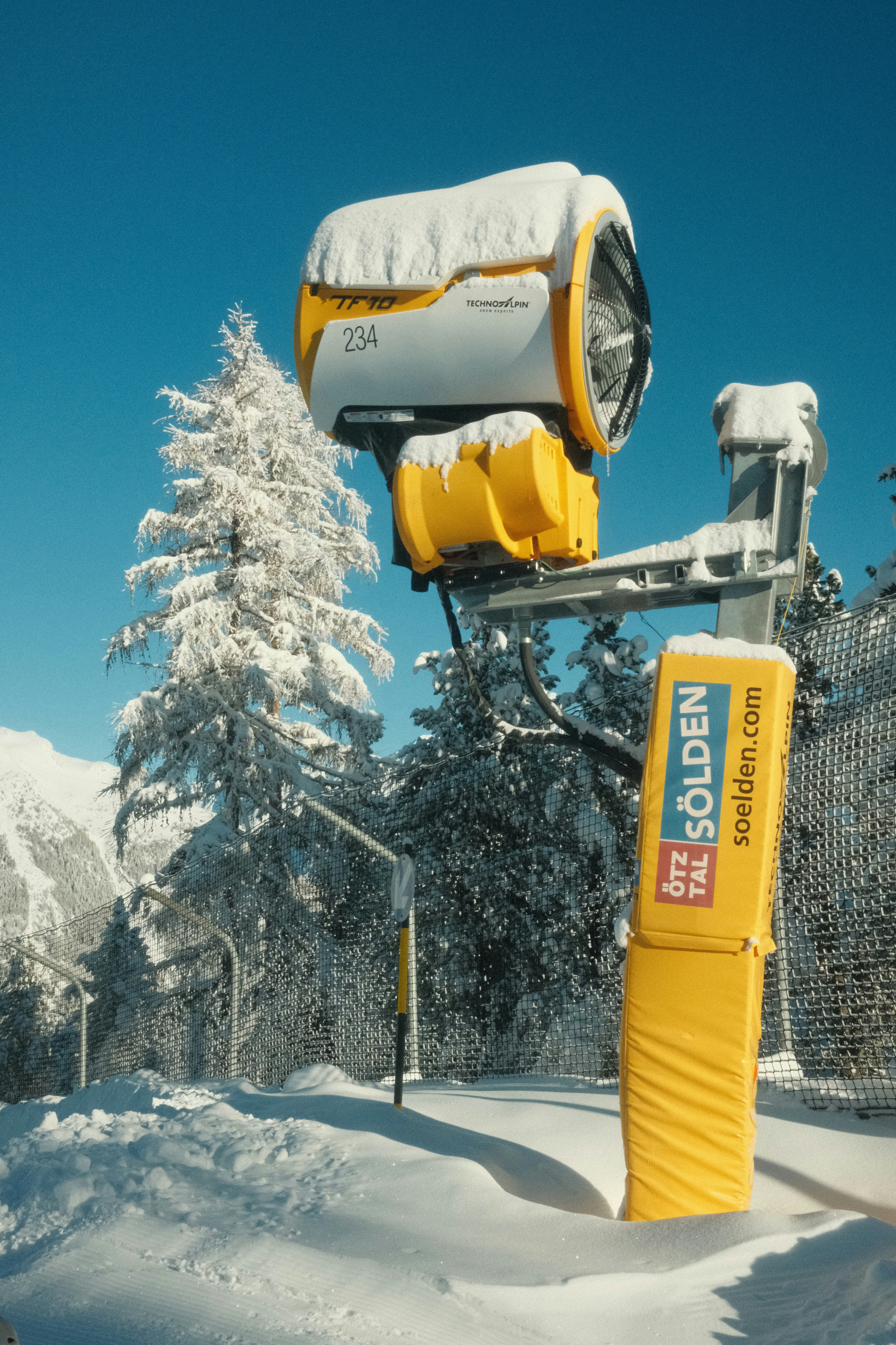 Winter's Yellow Sentinel: Snowmaking Crane Against an Alpine Blue