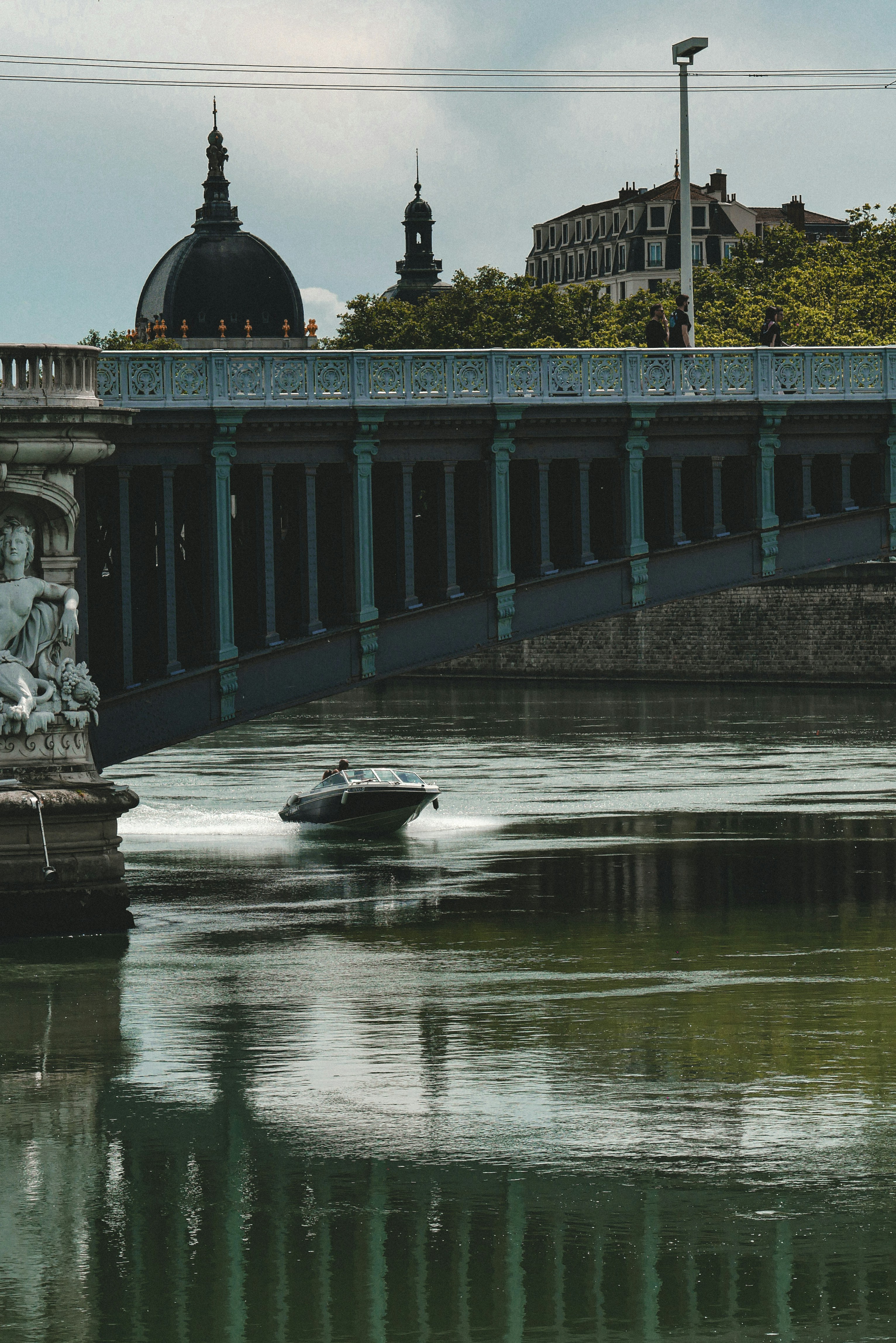 A boat traveling down a river next to a bridge photo – Free Lyon Image ...