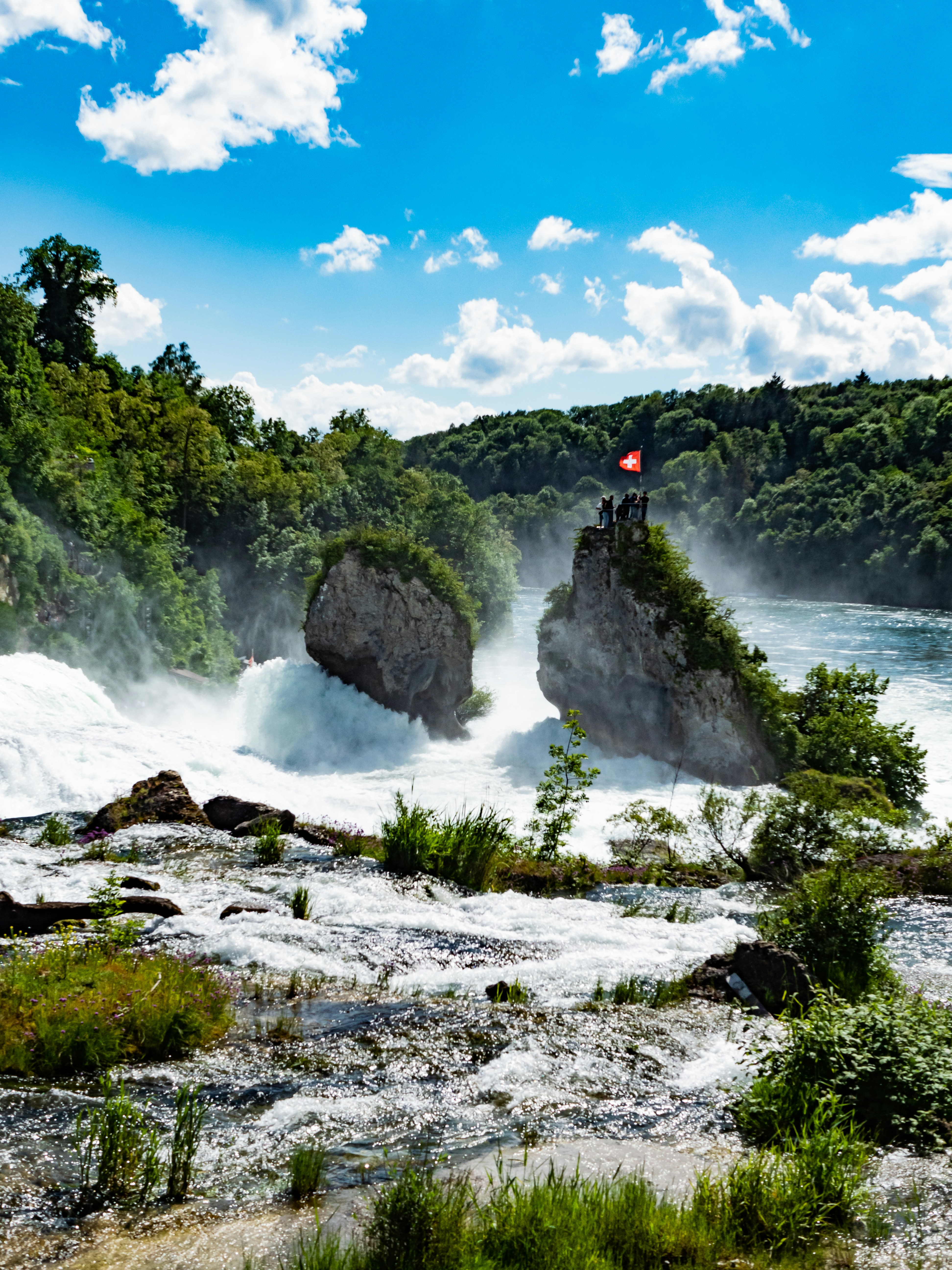 Red flag on a craggy islet flanked by roaring rapids