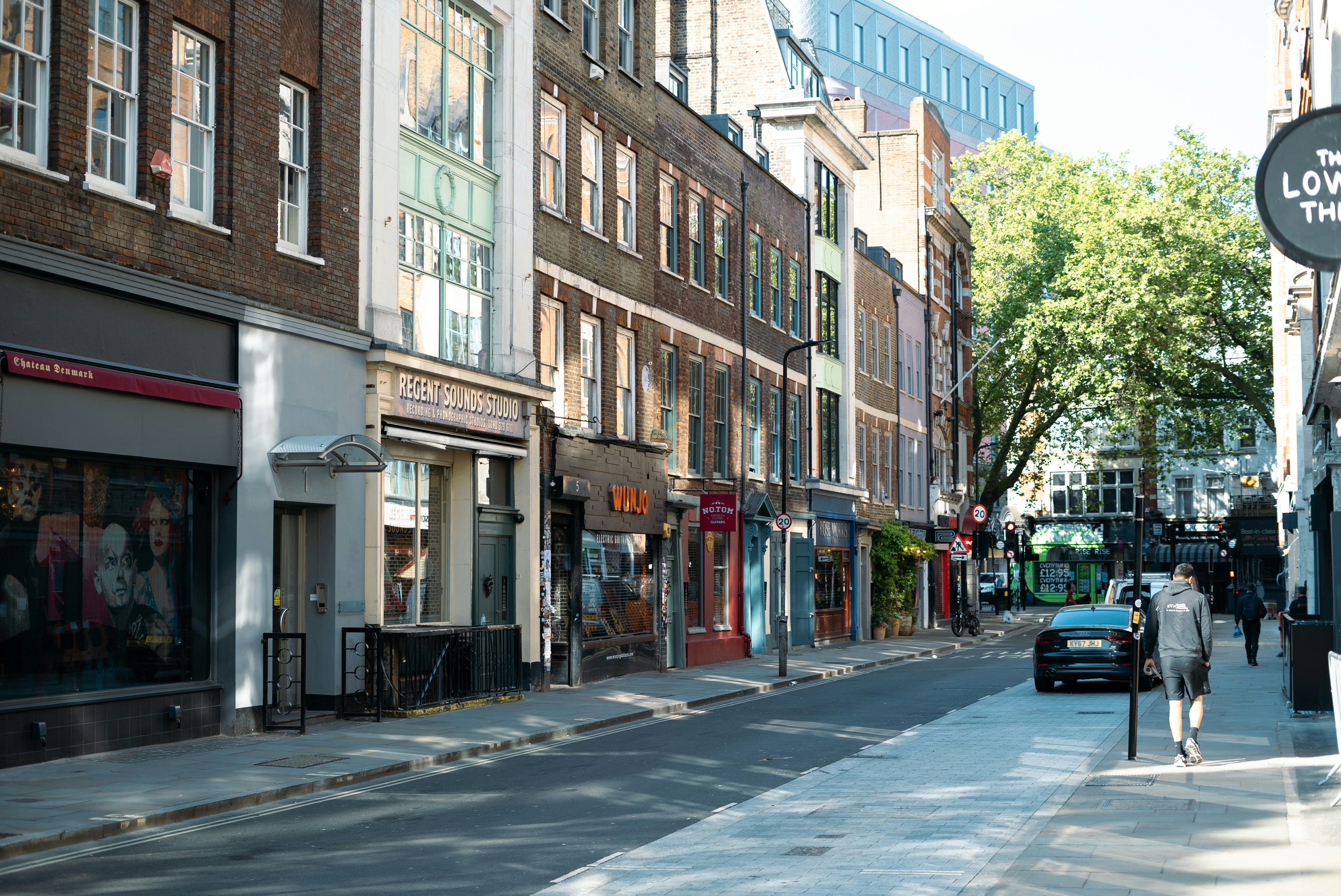 a man walking down a street next to tall buildings