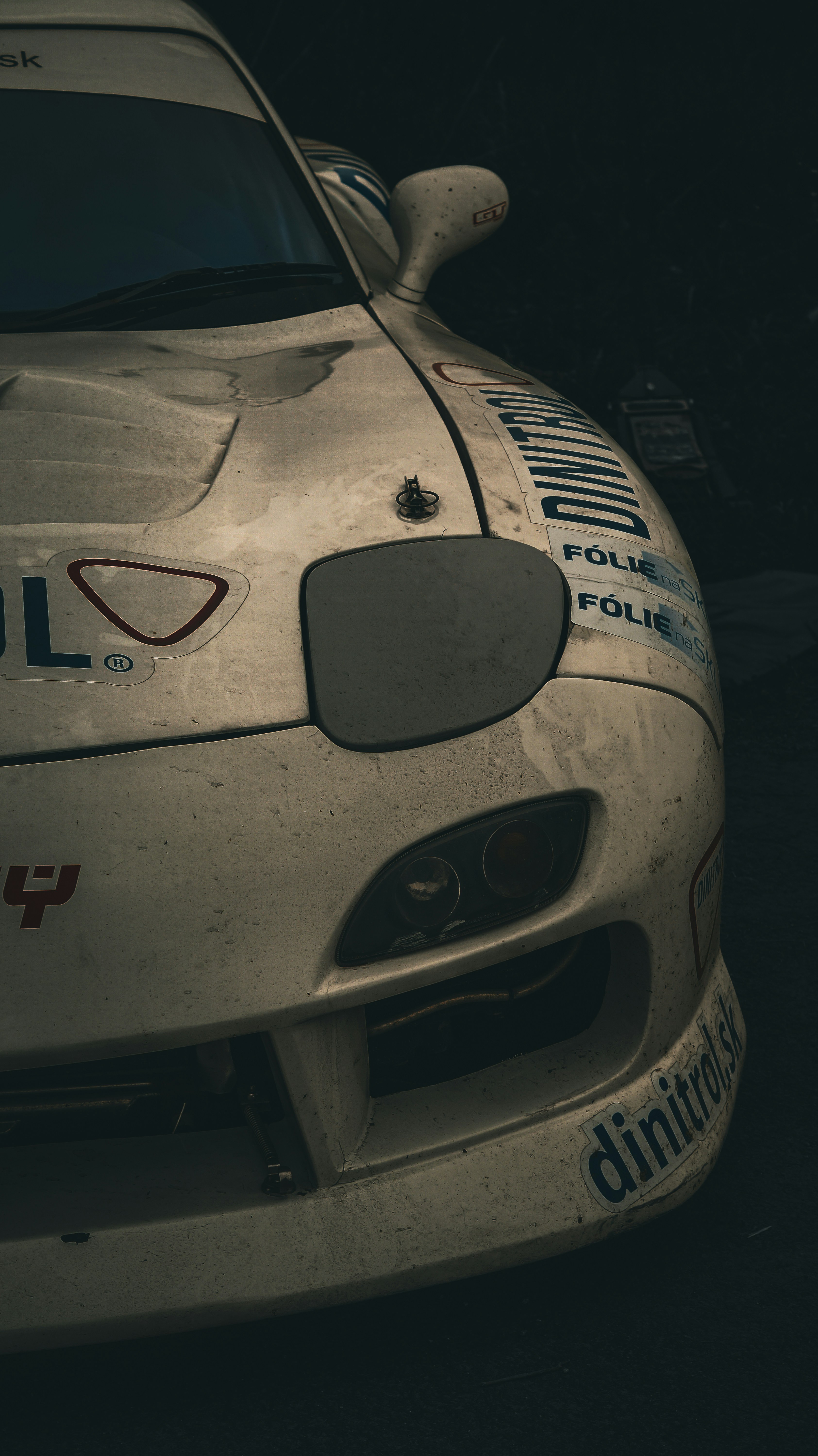 Close-up of a weathered racing car showcasing its worn exterior and sponsor logos, reflecting a legacy of speed and competition.