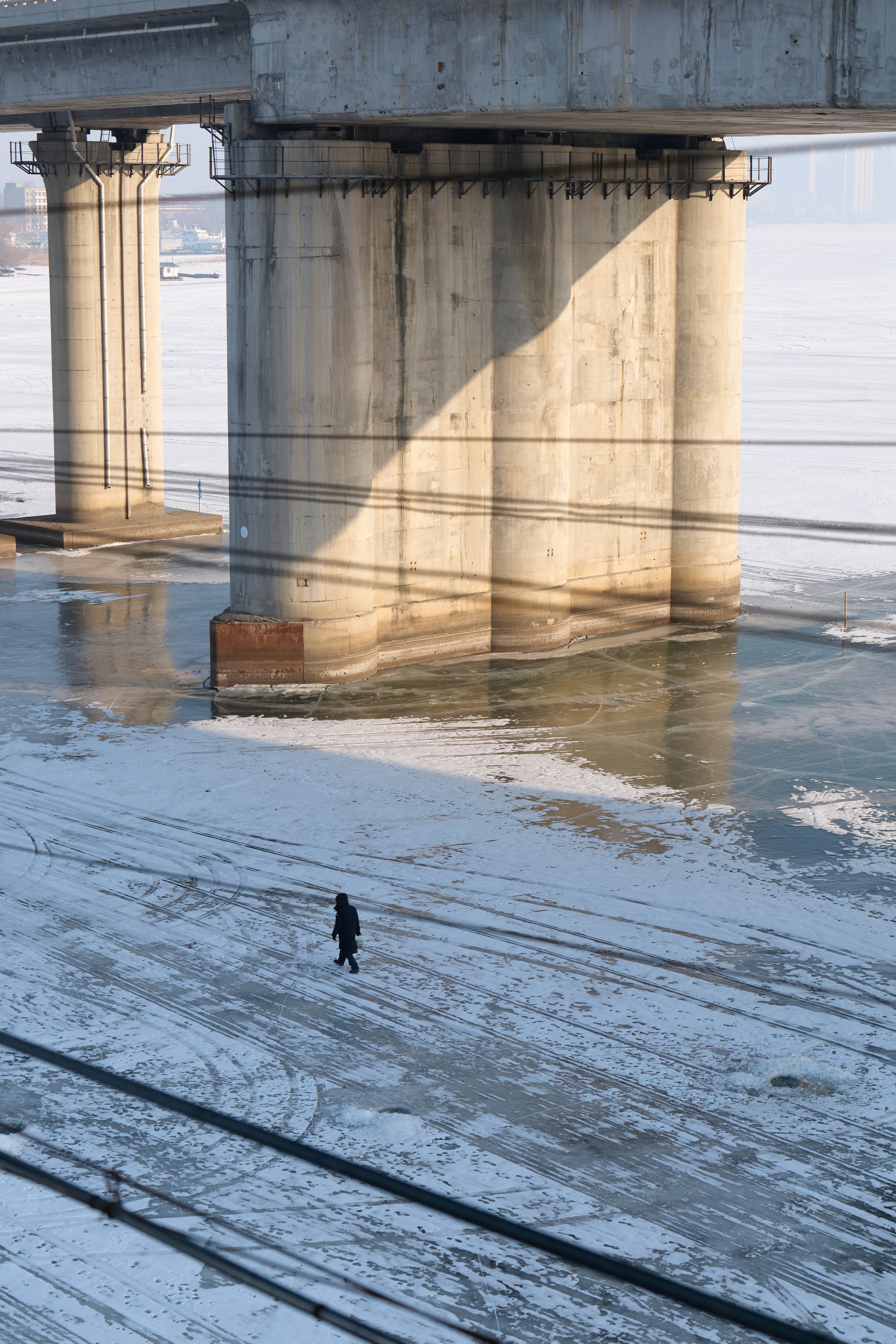 Solitary Step Under the Bridge: Ice, Shadow, and Steel