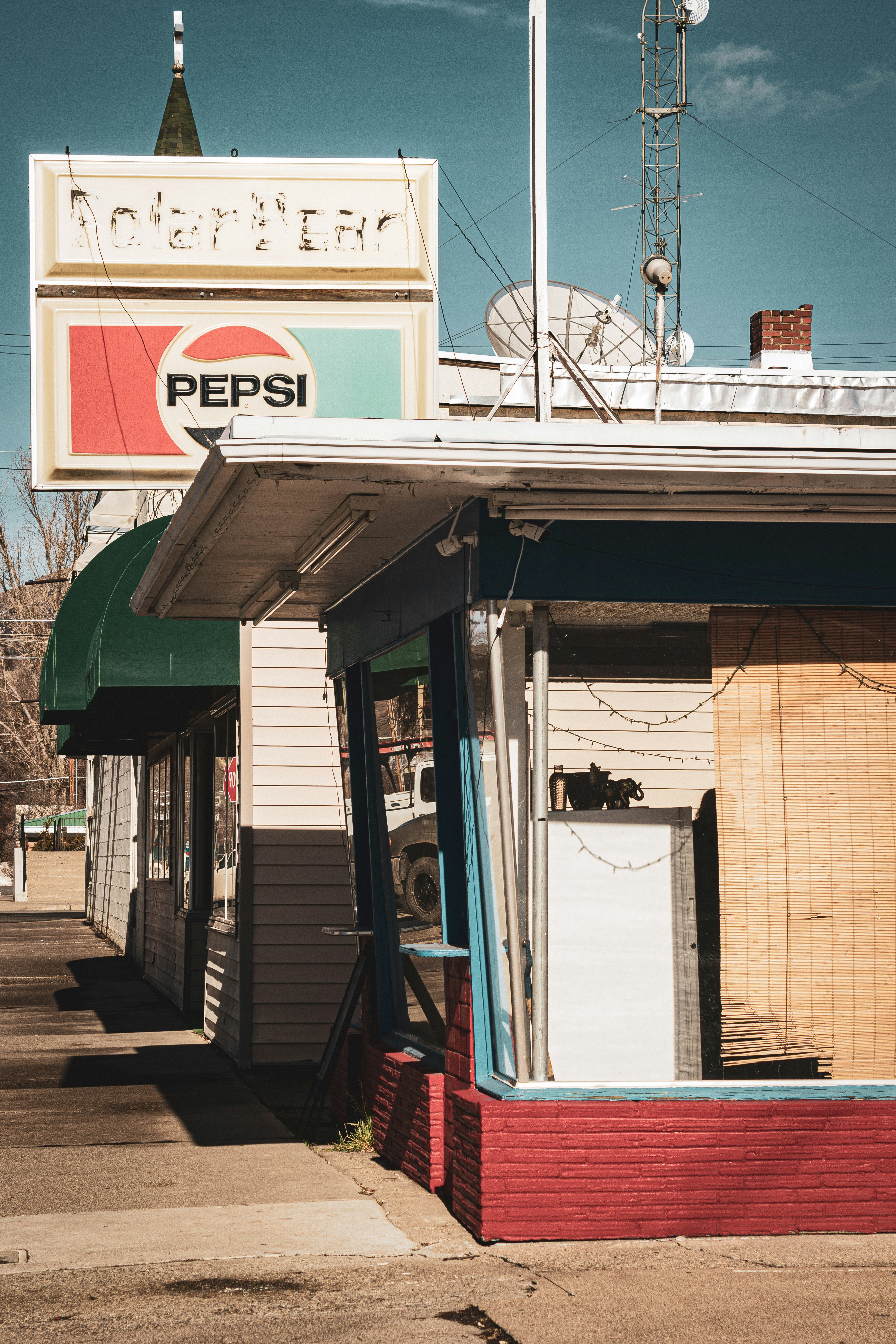 A vintage storefront featuring a prominent Pepsi sign and colorful architectural details, evoking a sense of nostalgia. The scene captures the essence of a small-town atmosphere.
