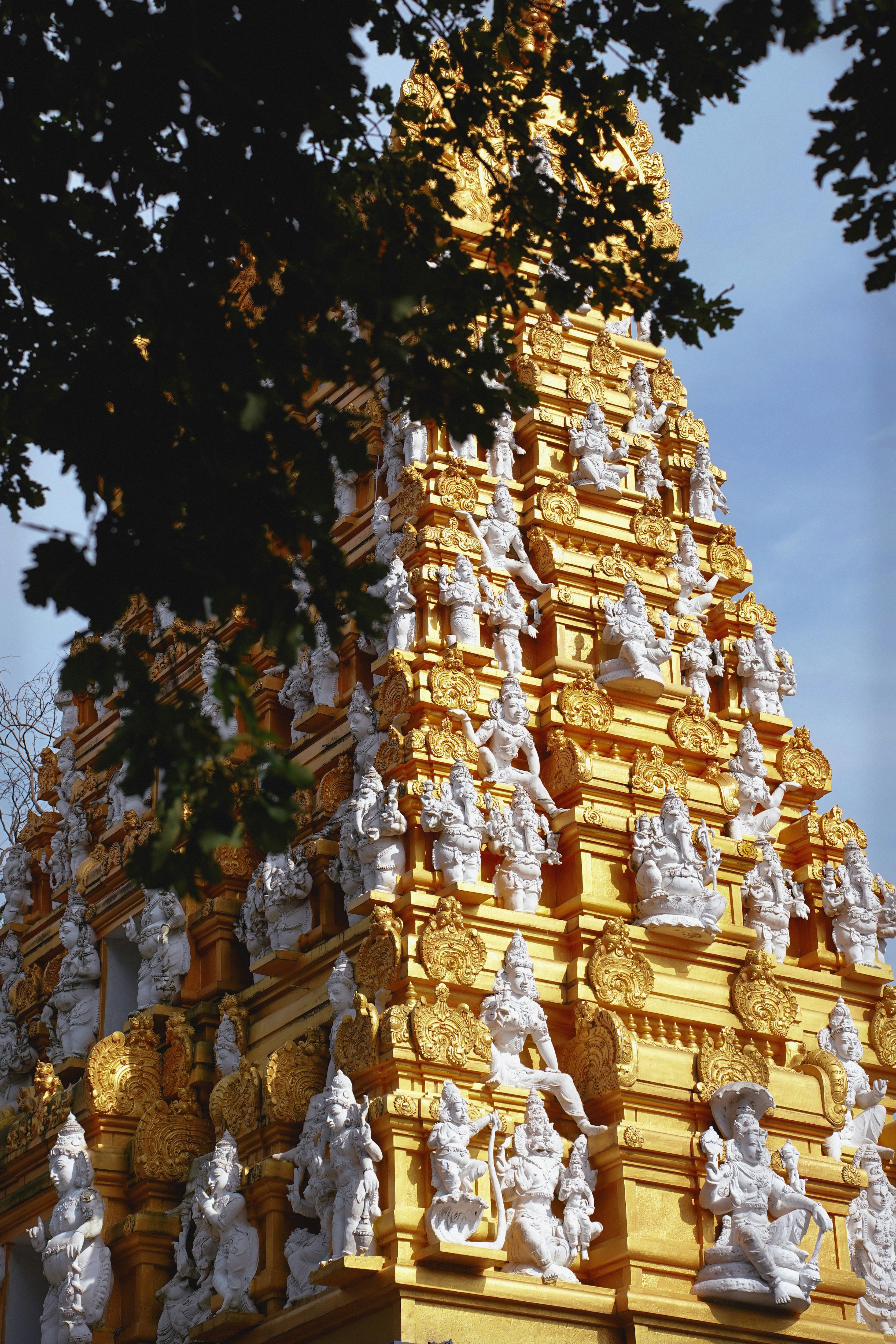 Gilded Shikhara Ashara: Sculpted Sanctum Rising Among Foliage