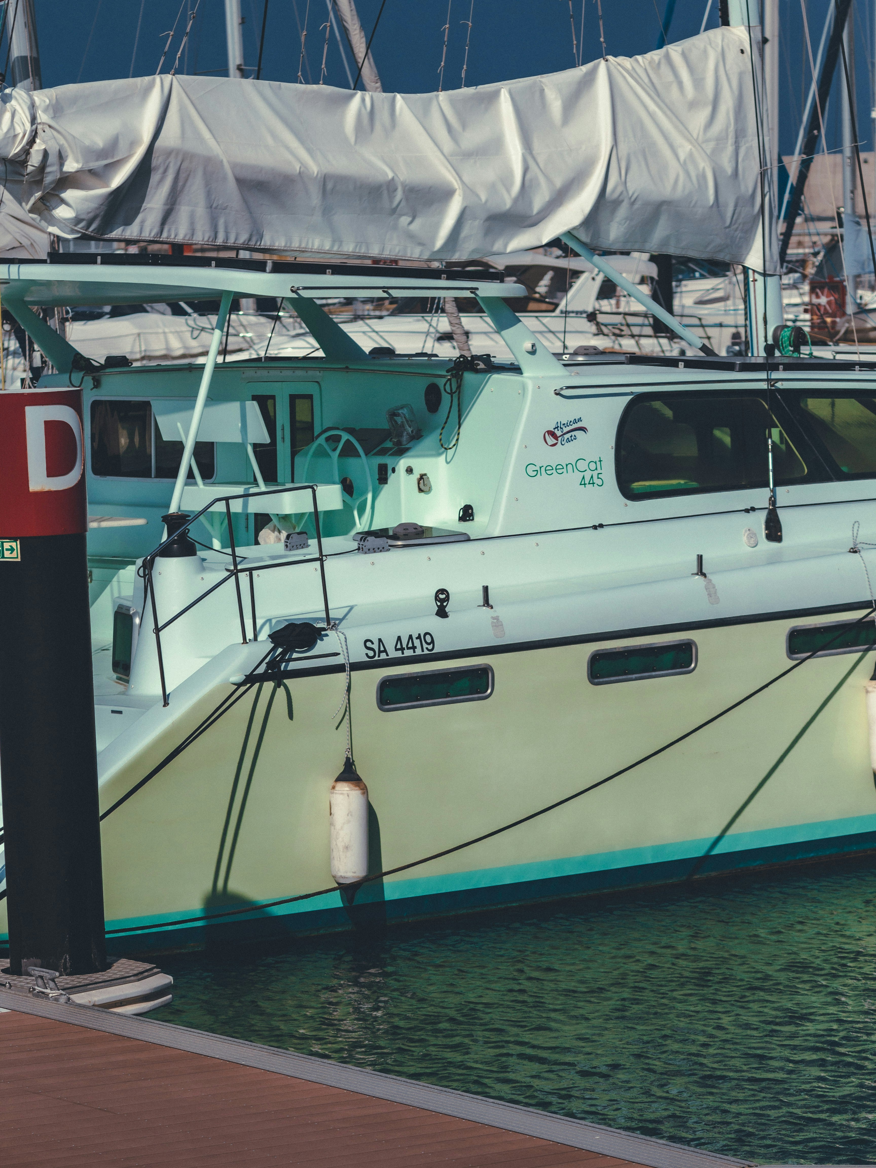 GreenCat 445 at the Marina: Teal Trim and a Covered Sail