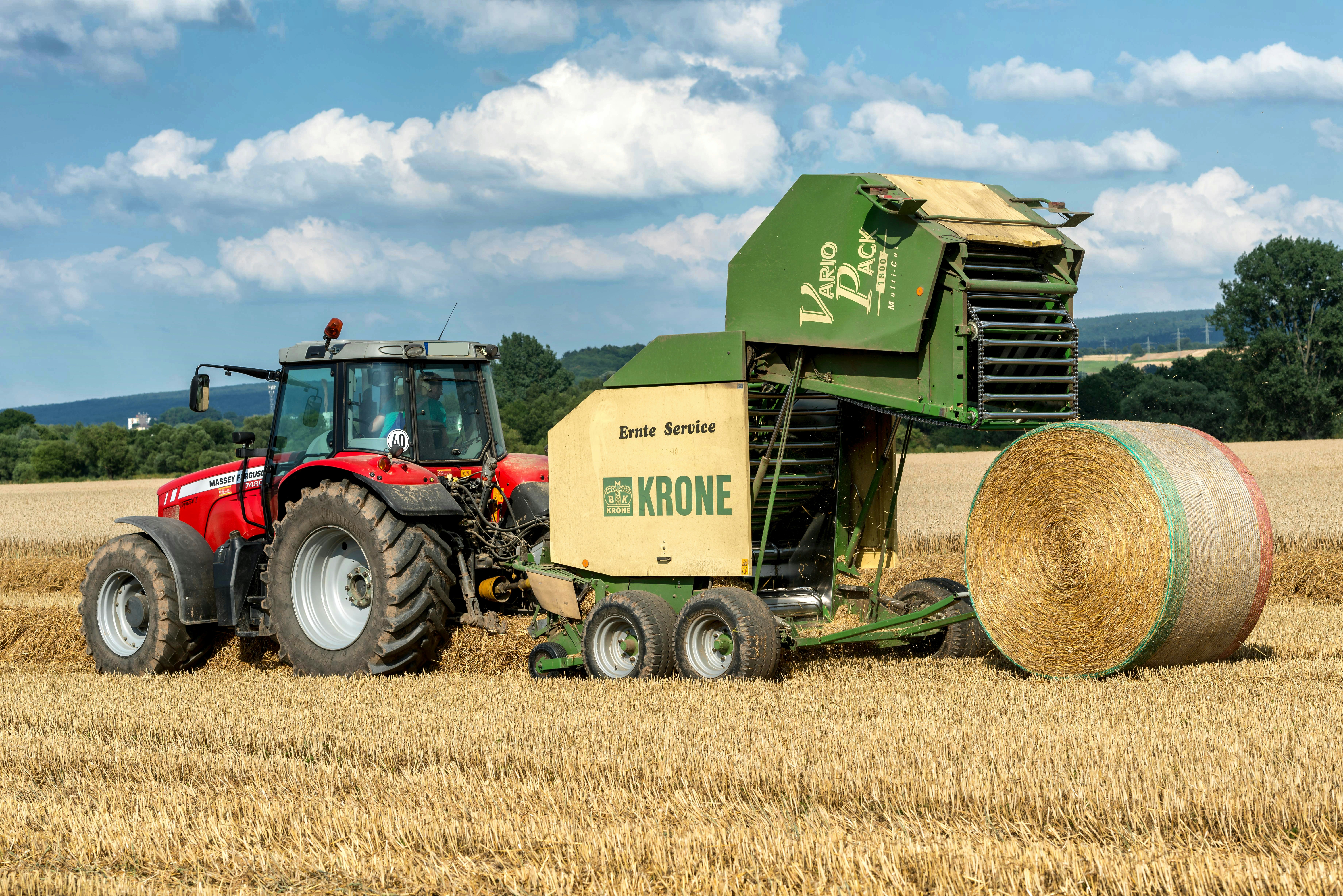 A tractor pulling a bale of hay behind it photo – Free Deutschland ...