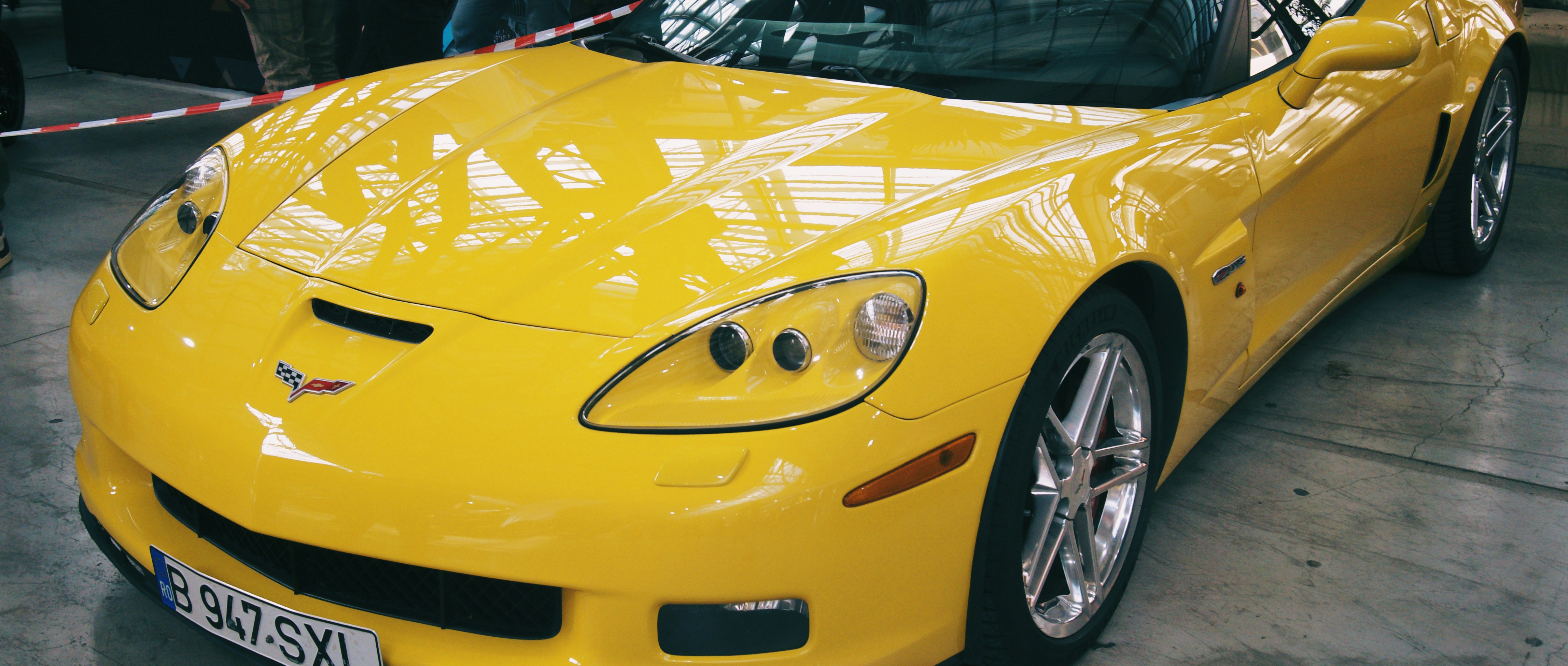 Sunlit Corvette: Sculpted Curves and Reflective Yellow in a Showroom