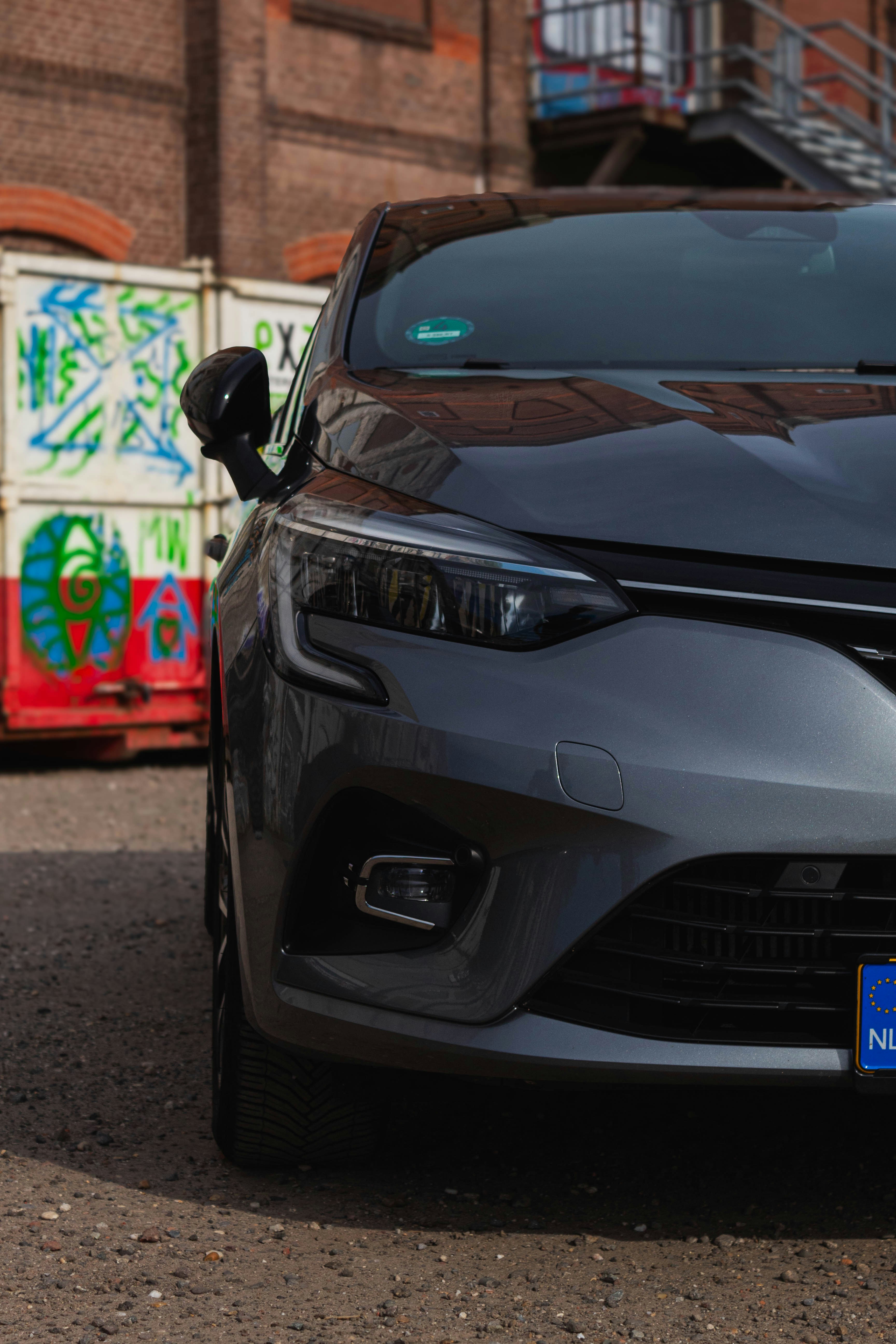 Urban Chrome at the Front Bumper: A Sedan Amid Graffiti and Brick