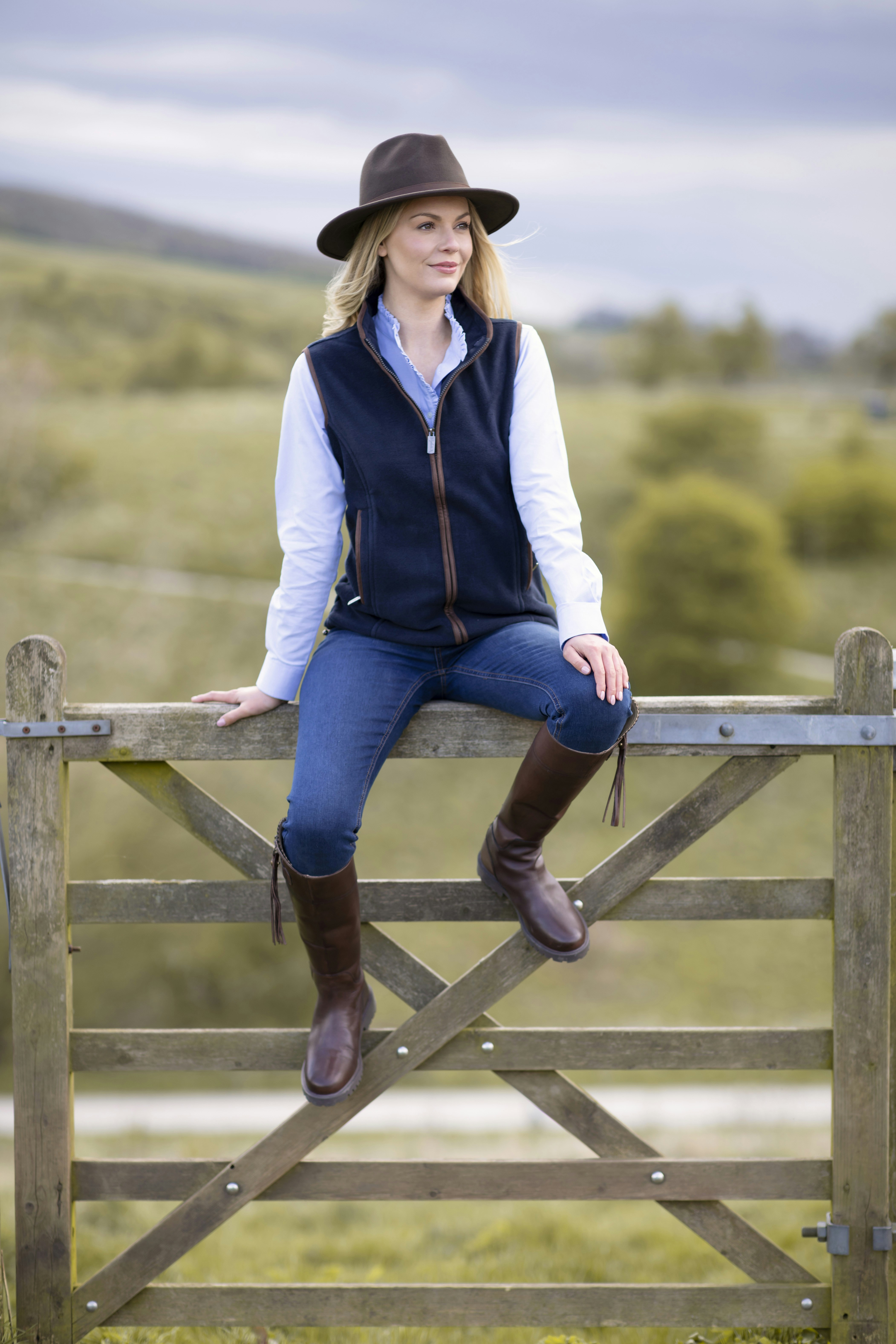 A woman sitting on a fence wearing a hat photo – Free Ladies waistcoat ...