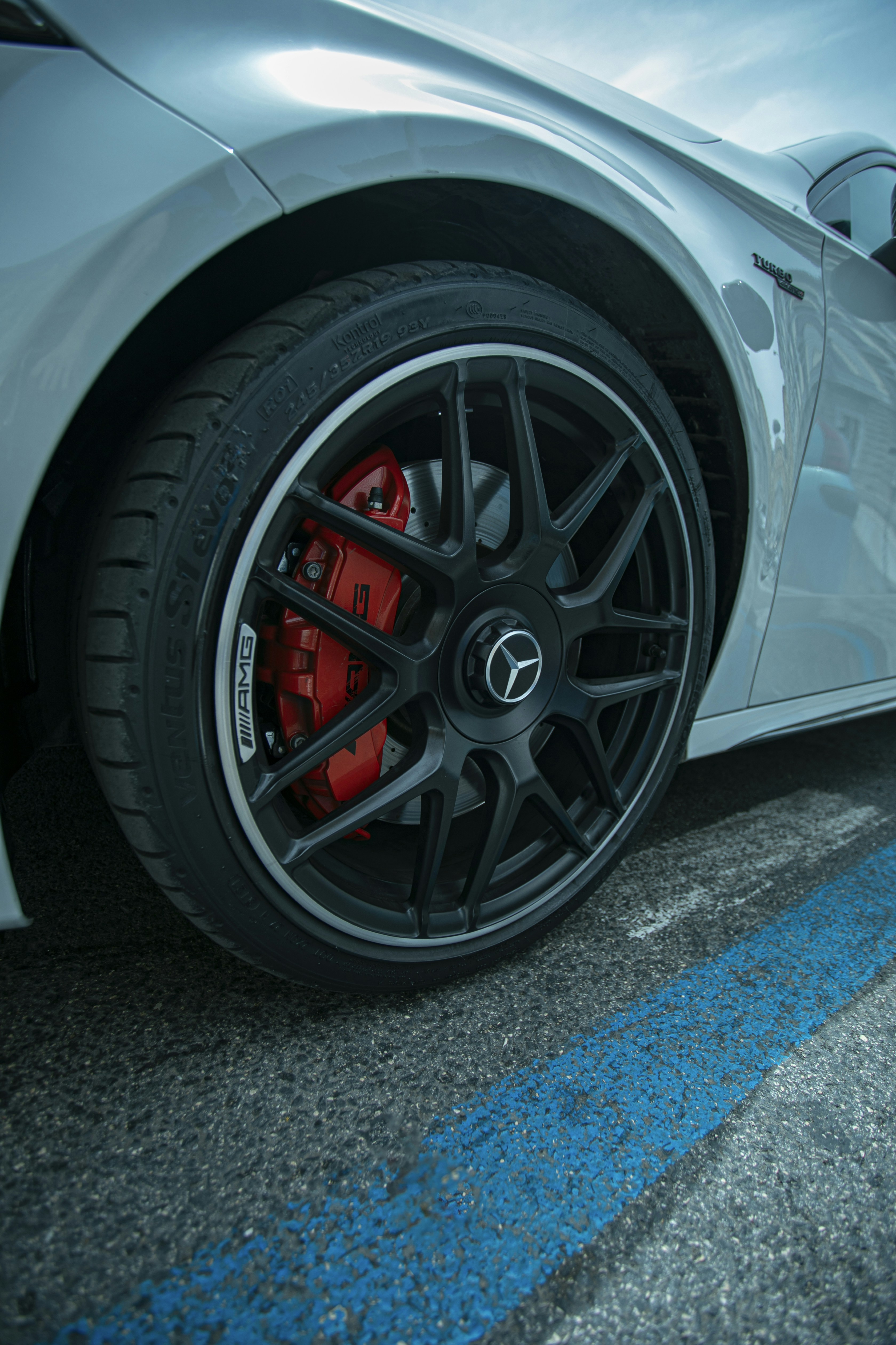 Close-Up of a AMG Rim and Red Brake Caliper Under Car Swoosh
