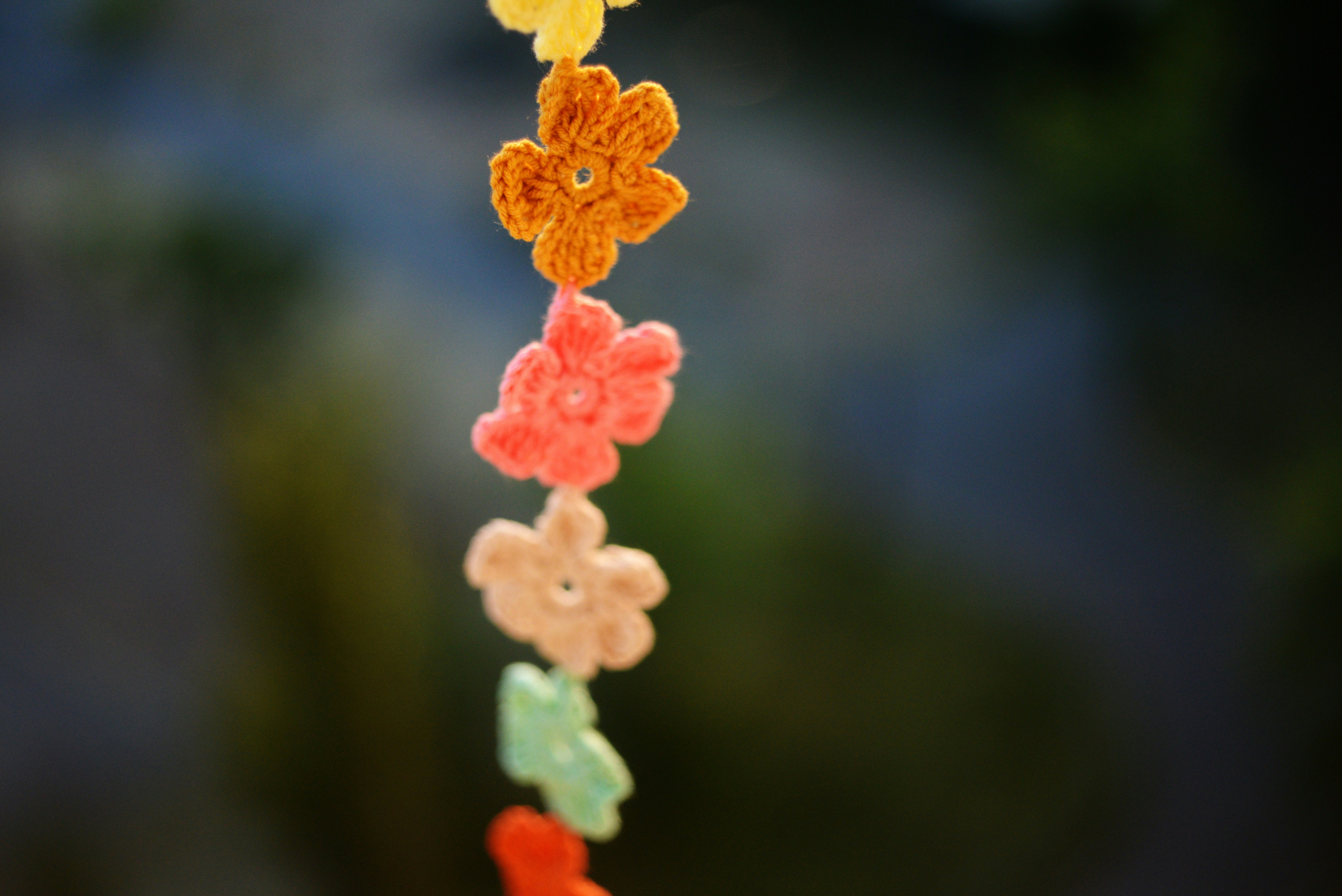 Vertical string of crochet flowers blurred against a soft backdrop