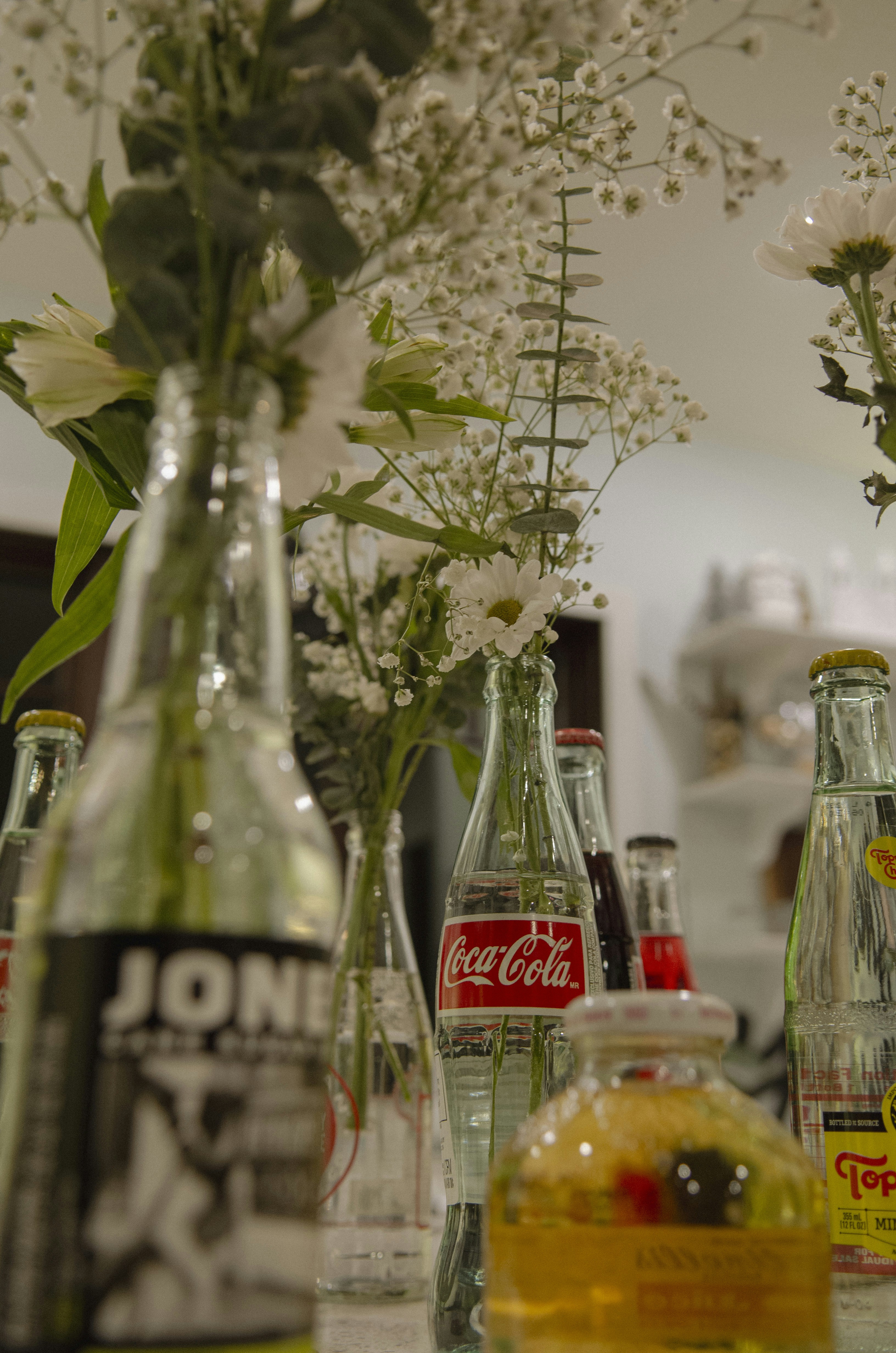 A Still Life of Glass Bottles and White Florals in Soft Indoor Light