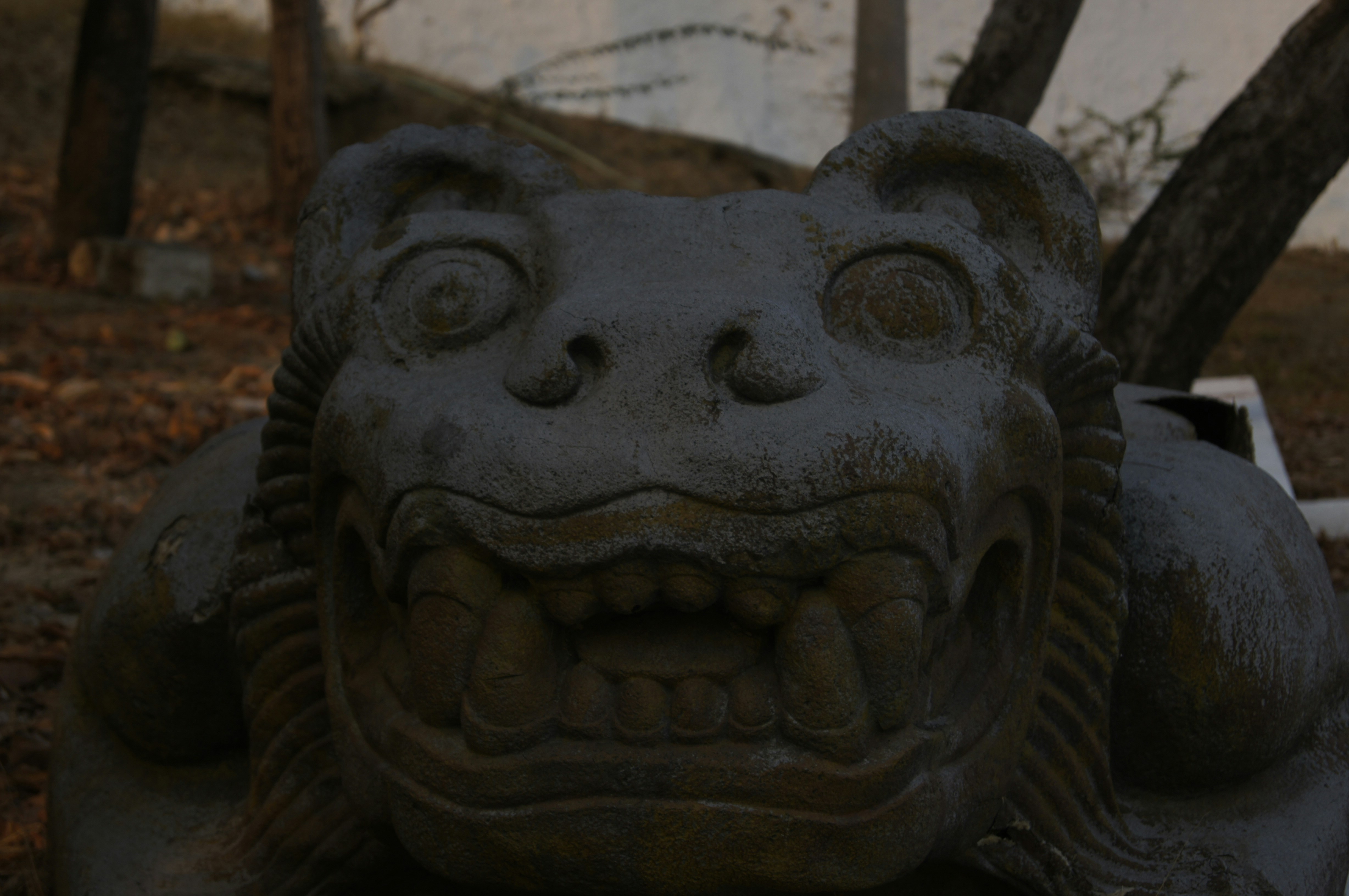 Stone Guardian in the Dusk: A Weathered Carving by the Water's Edge