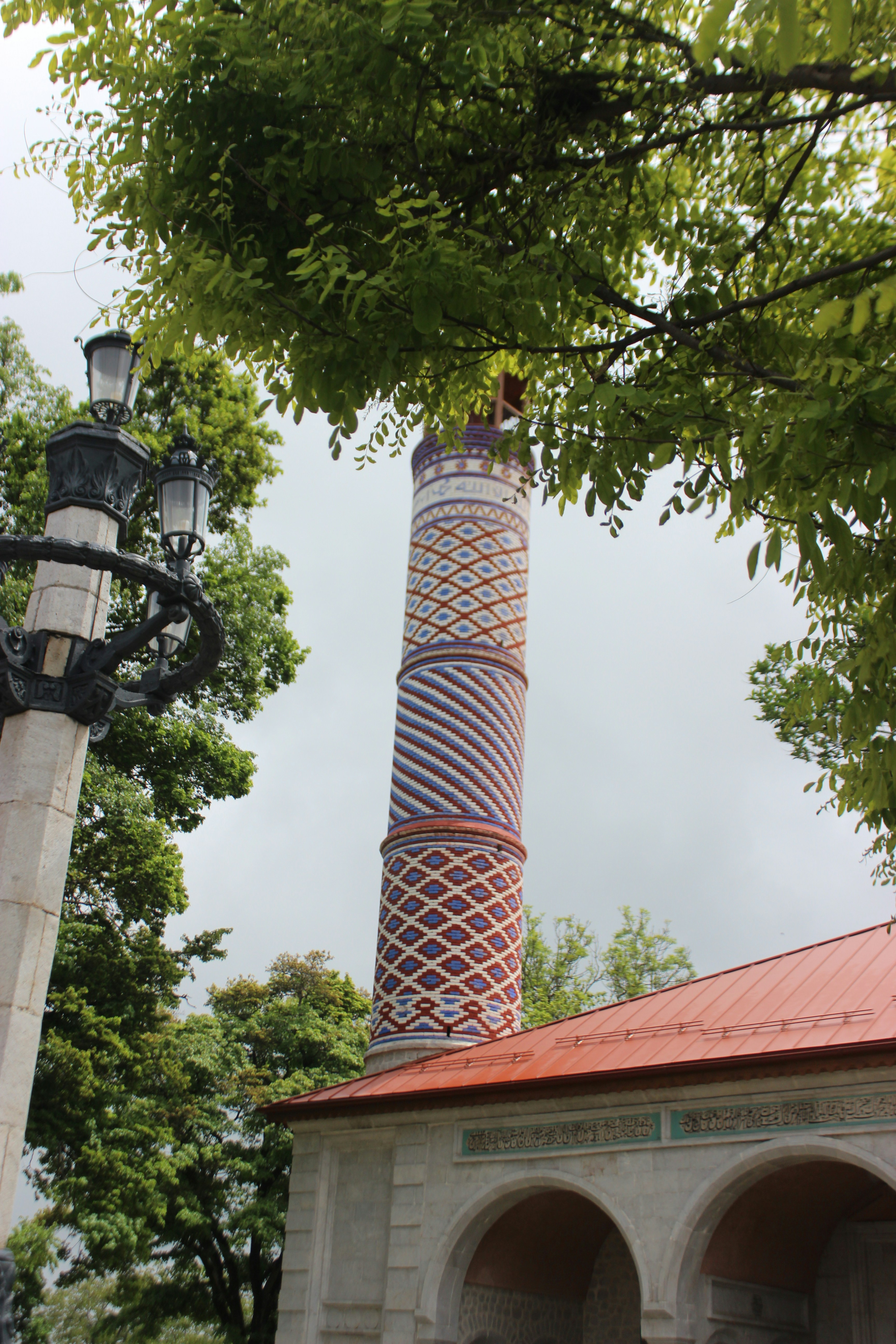 Colorful Tile Column Rising in a Temple Courtyard Framed by Green Canopy