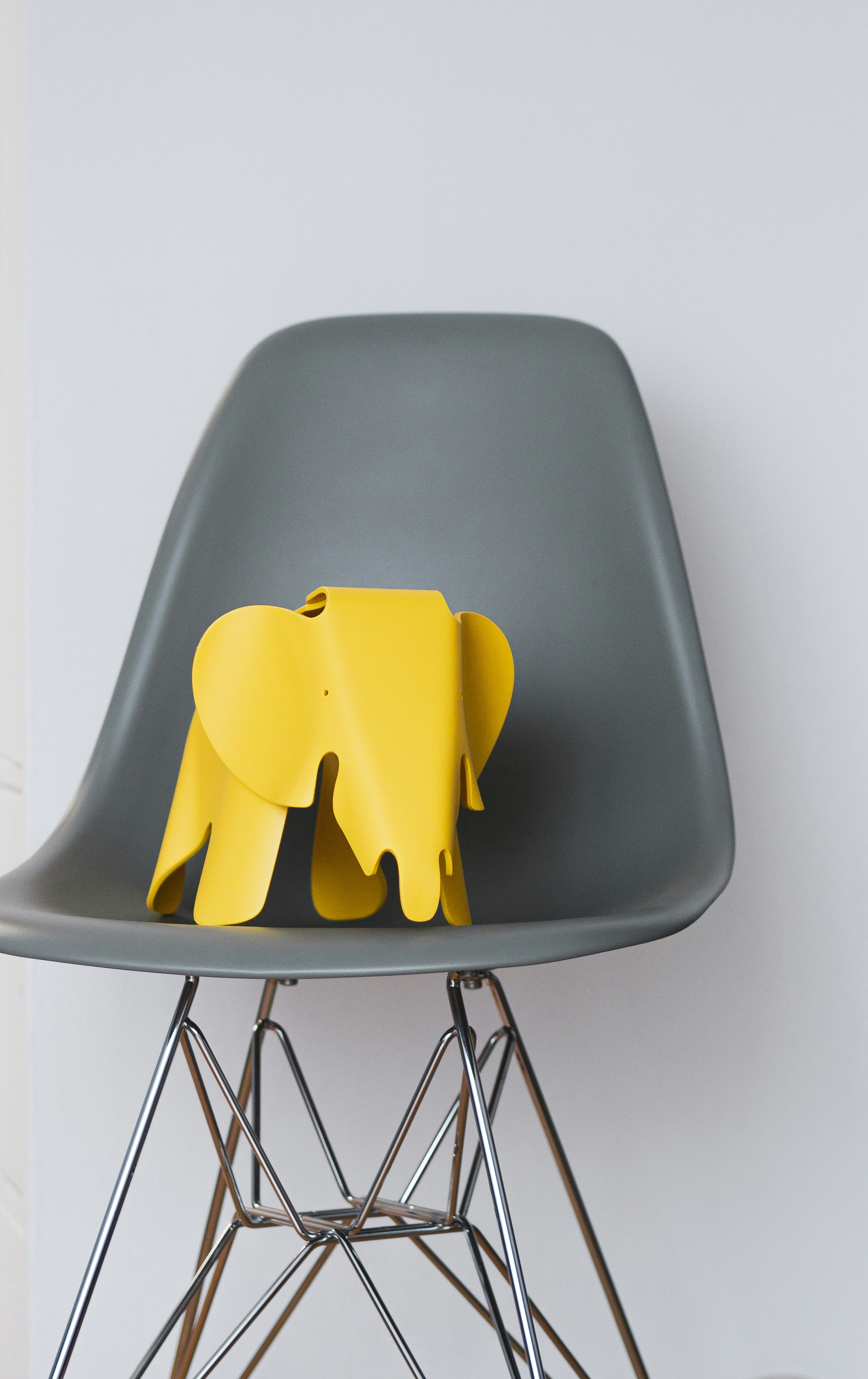 a yellow elephant sitting on top of a gray chairAnna