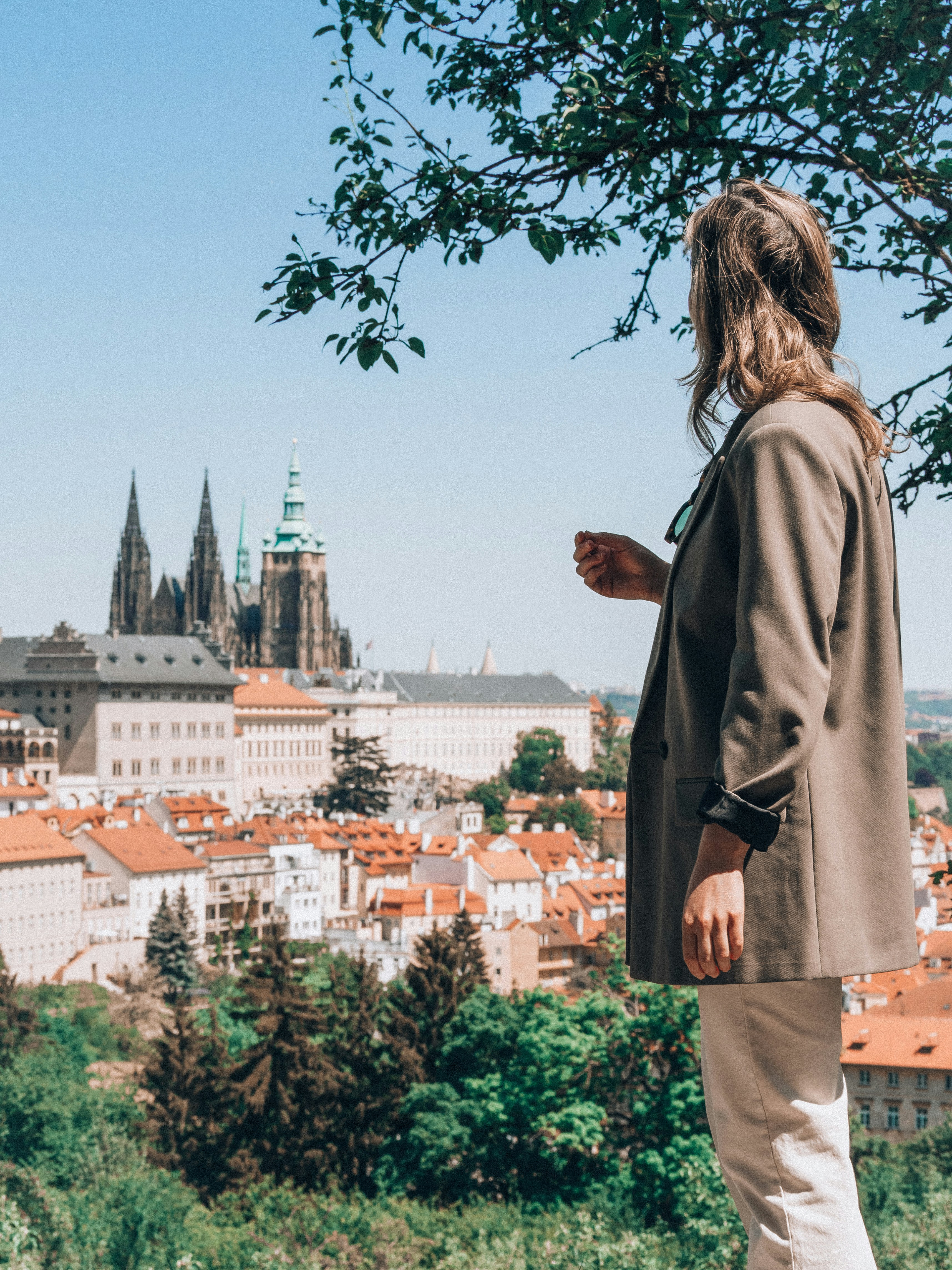 Tan-Coated Observer Framing a Spired Cityscape