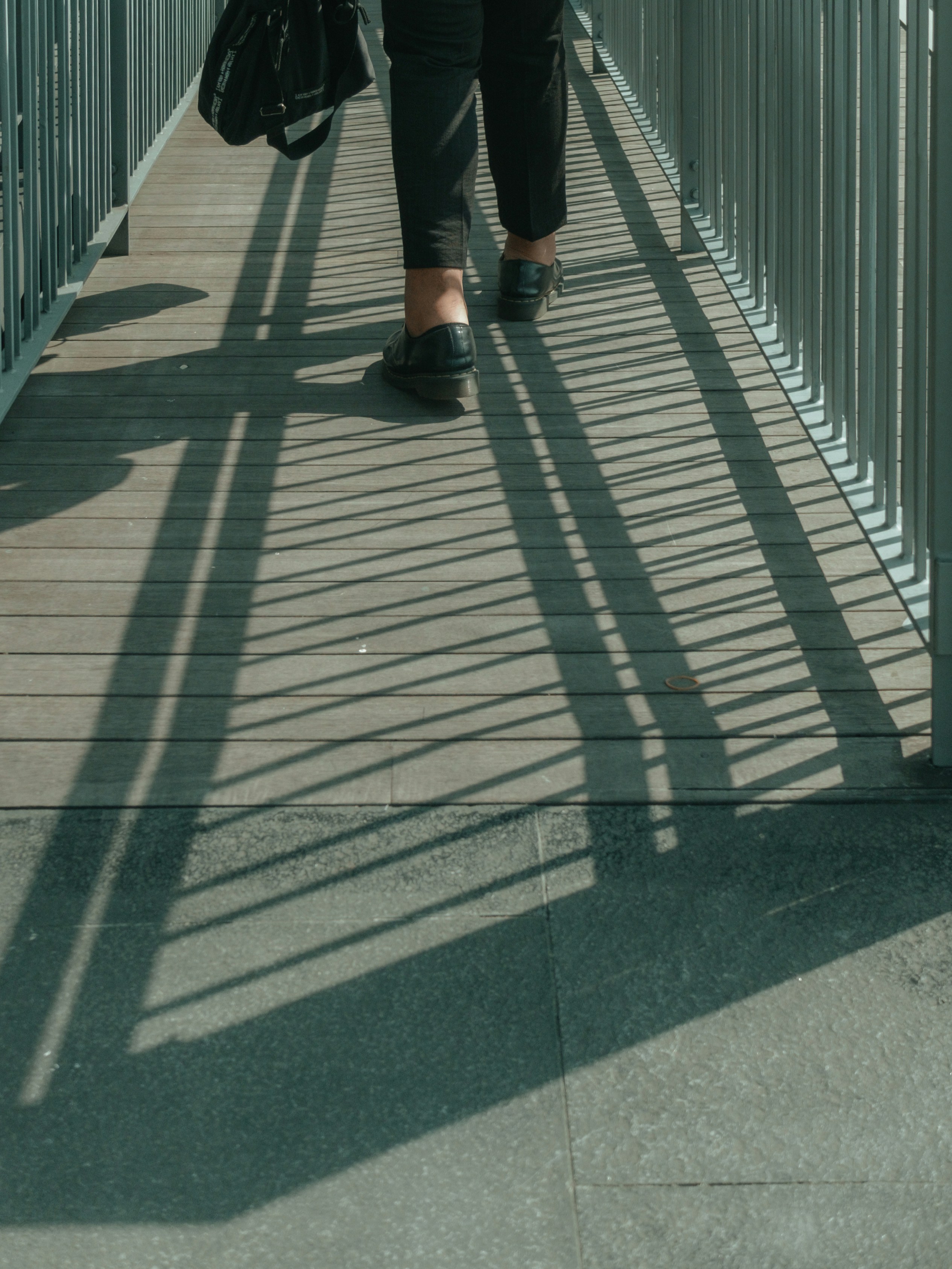 Boot Steps Through a Corridor of Rails: Shadowed Bridge Walk