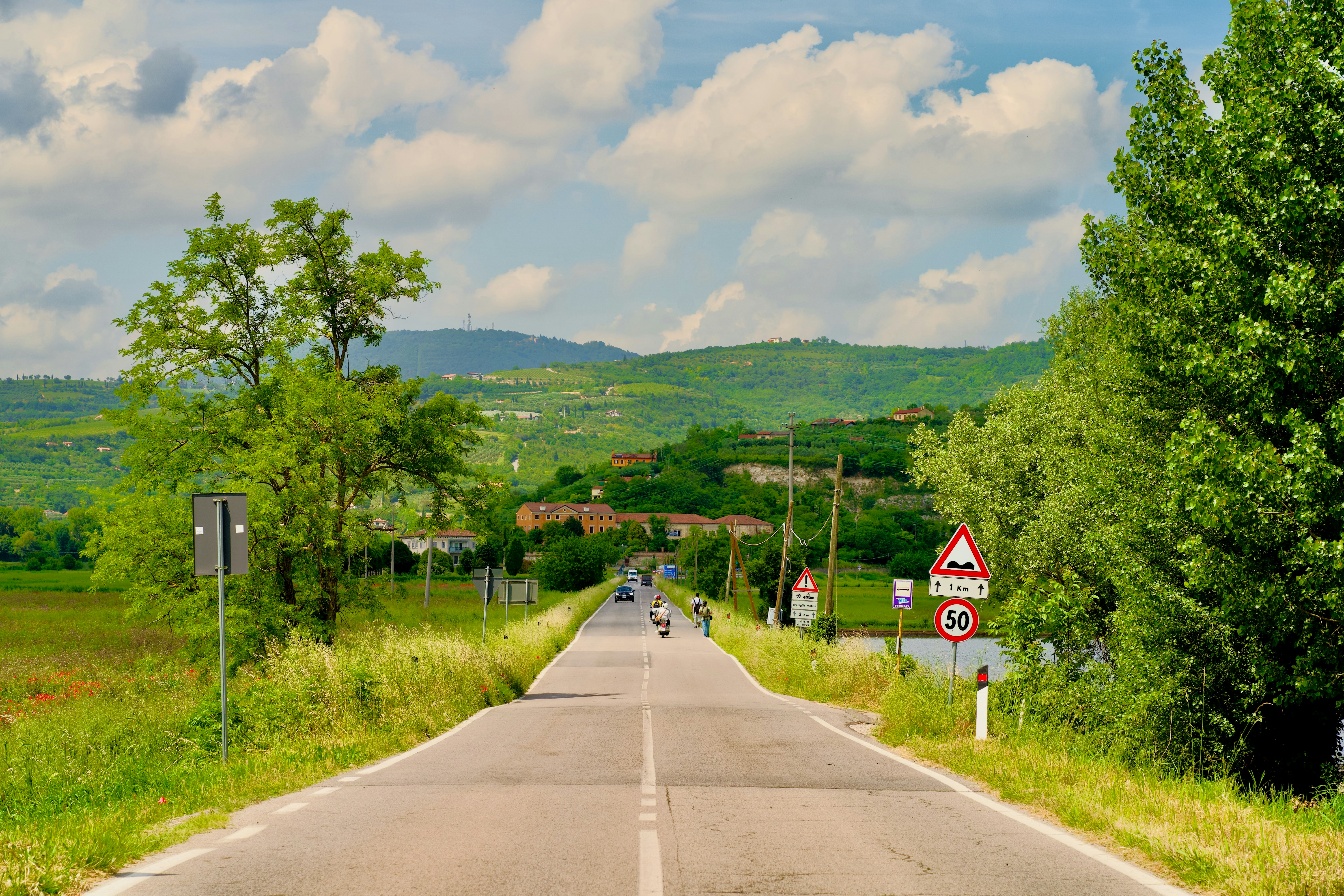 Cyclists on a Quiet Rural Ribbon Toward the Hills