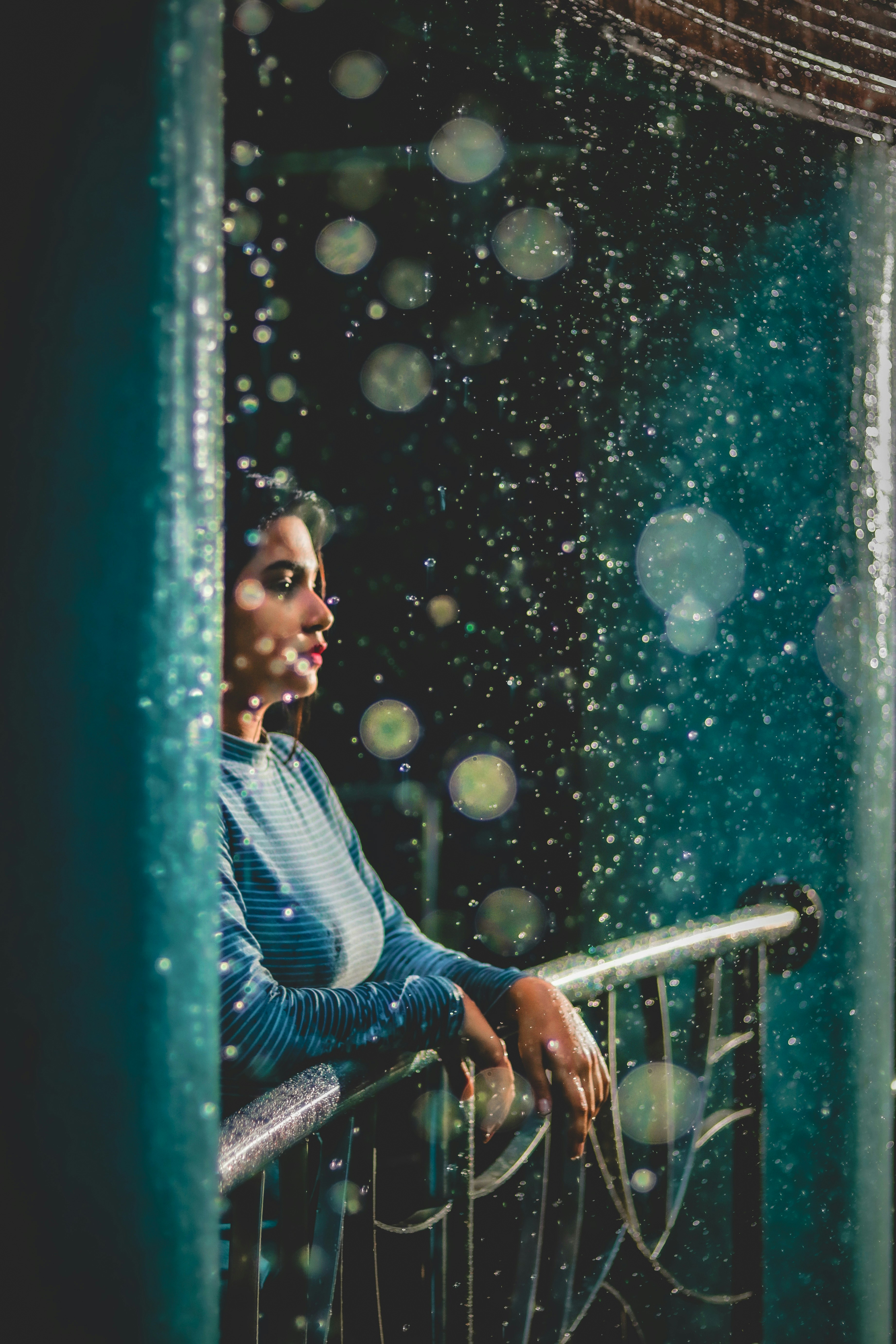 A woman standing on a balcony in the rain photo – Free Grey Image on ...