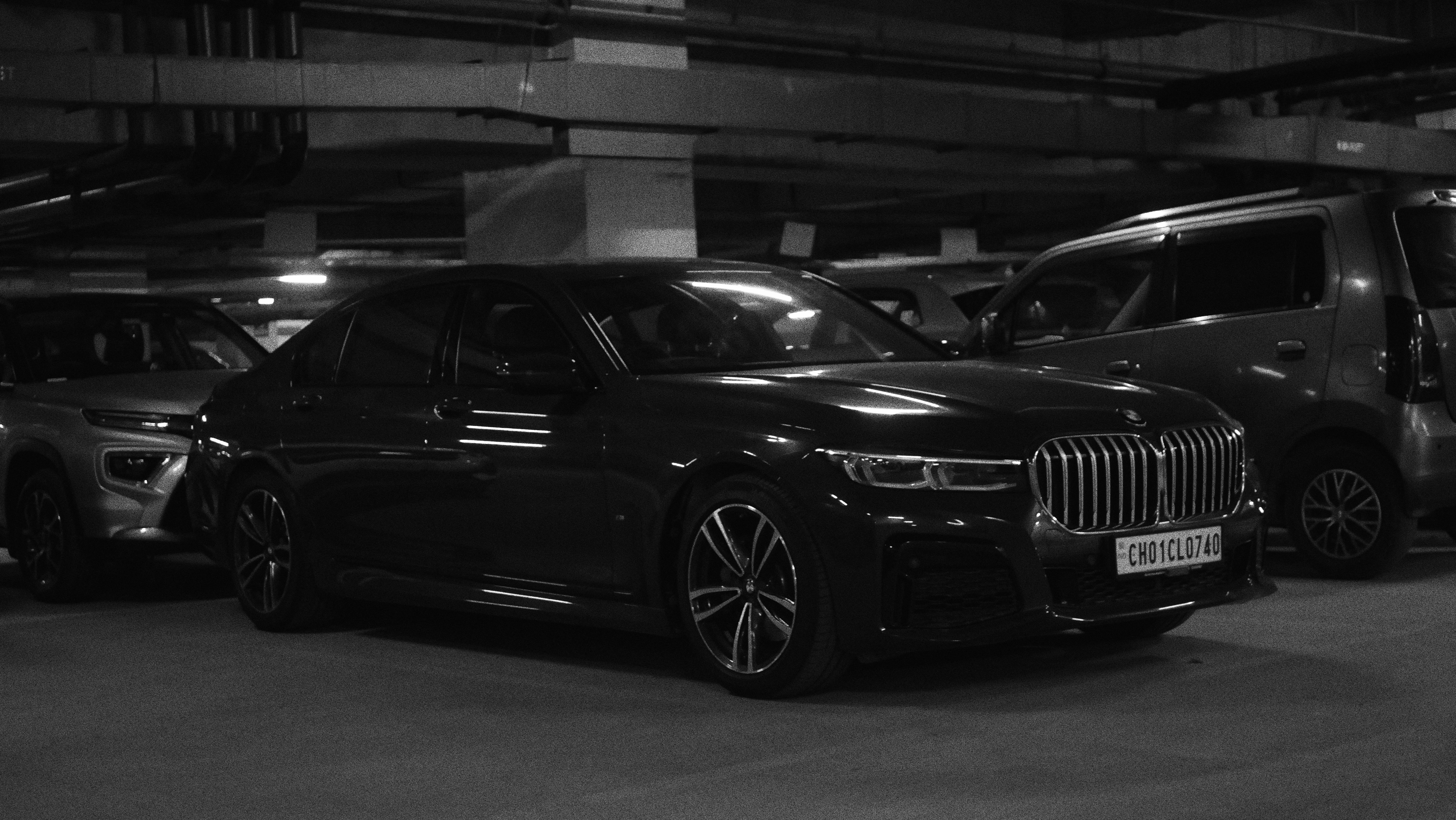 Midnight Gallery: A Black Sedan Among Silhouettes in a Parking Atrium