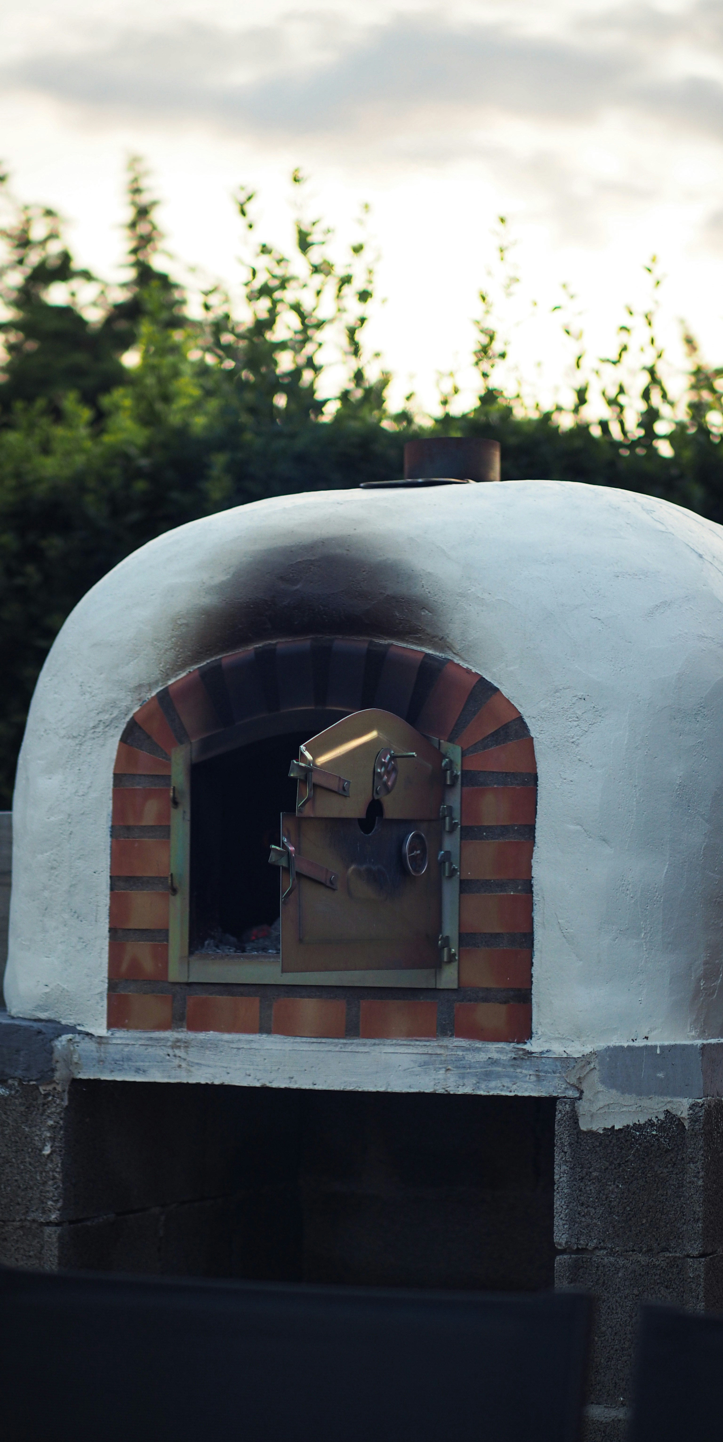 Chimney Oven at Dusk: Brick Arch, White Dome, and a Door of Steel