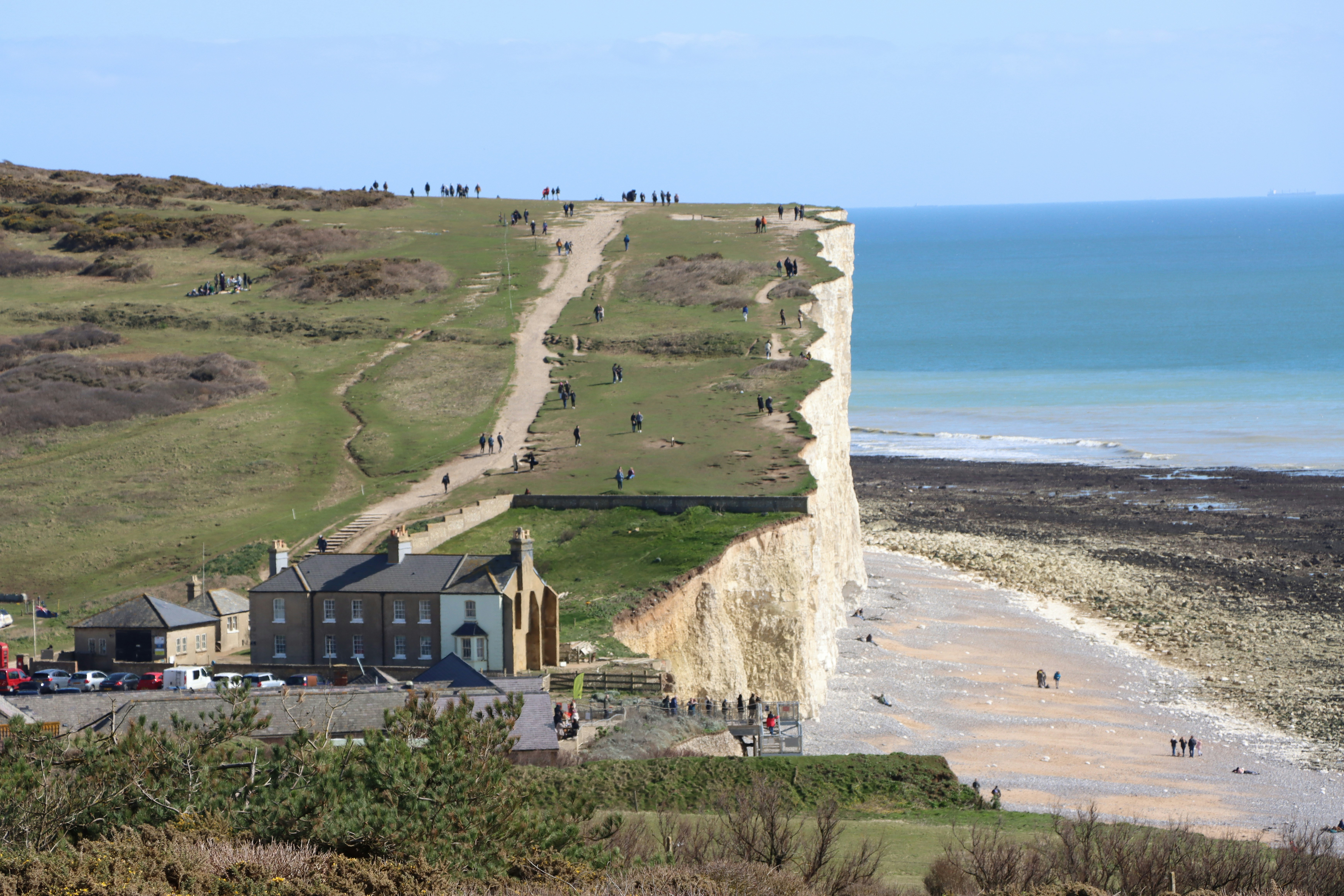 A group of people standing on top of a hill next to a beach photo ...