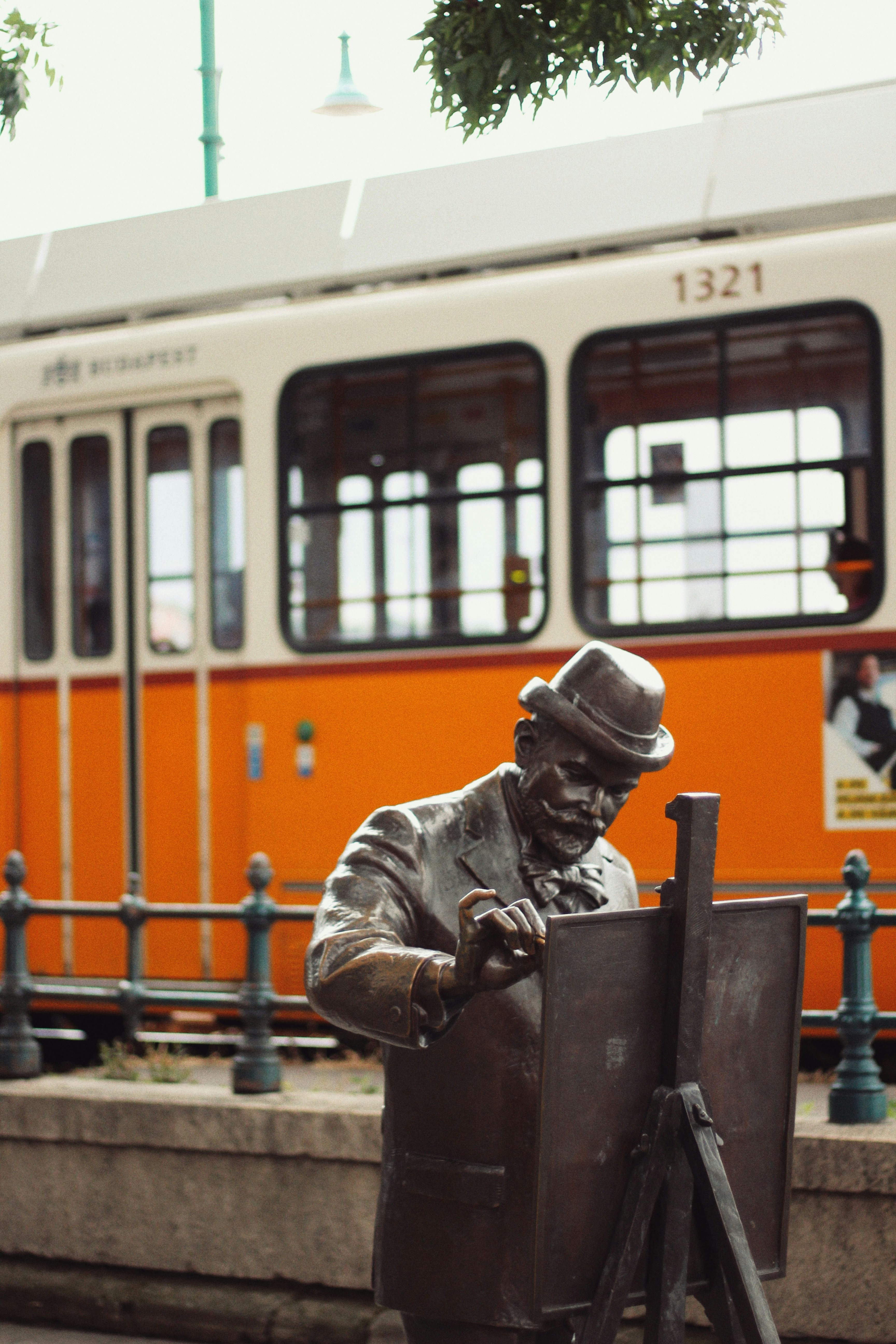 Bronze Painter at the Rails: A City Portrait Beside an Orange Streetcar
