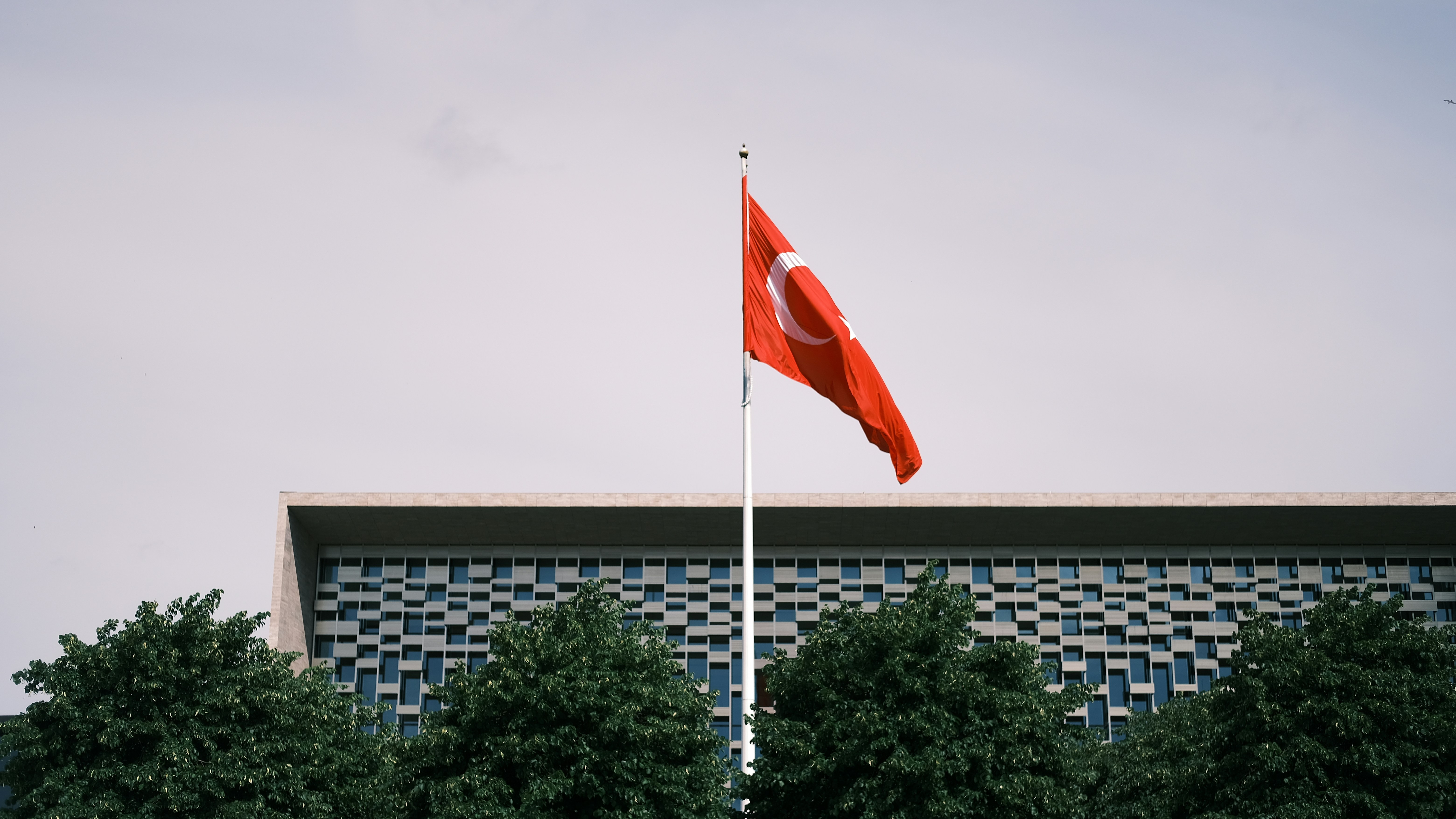Turkish Flag at the Pivot: A Red Banner Against a Mesh-Patterned Facade