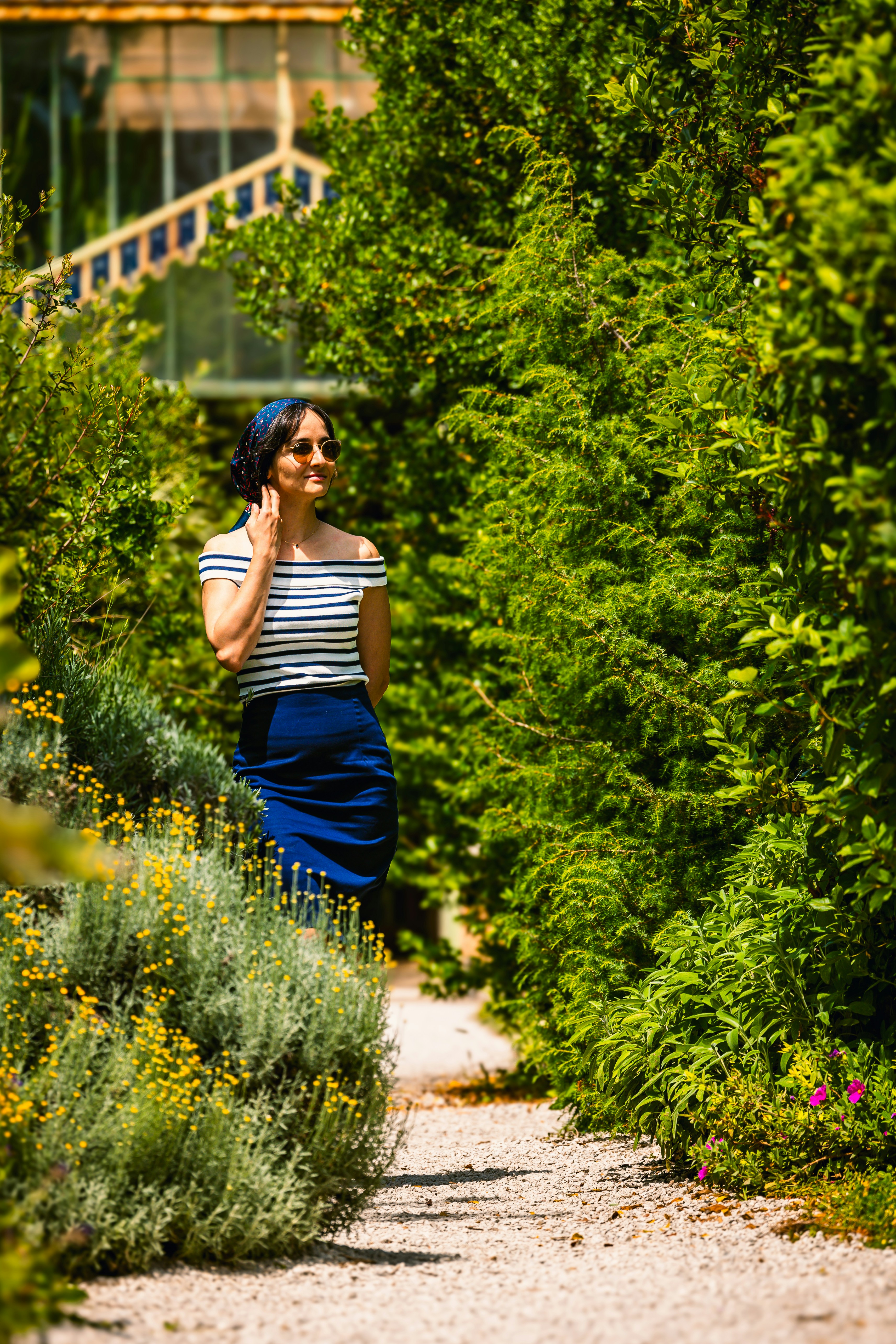 Sunlit Garden Corridor: Striped Ensemble Amid Green Hedges